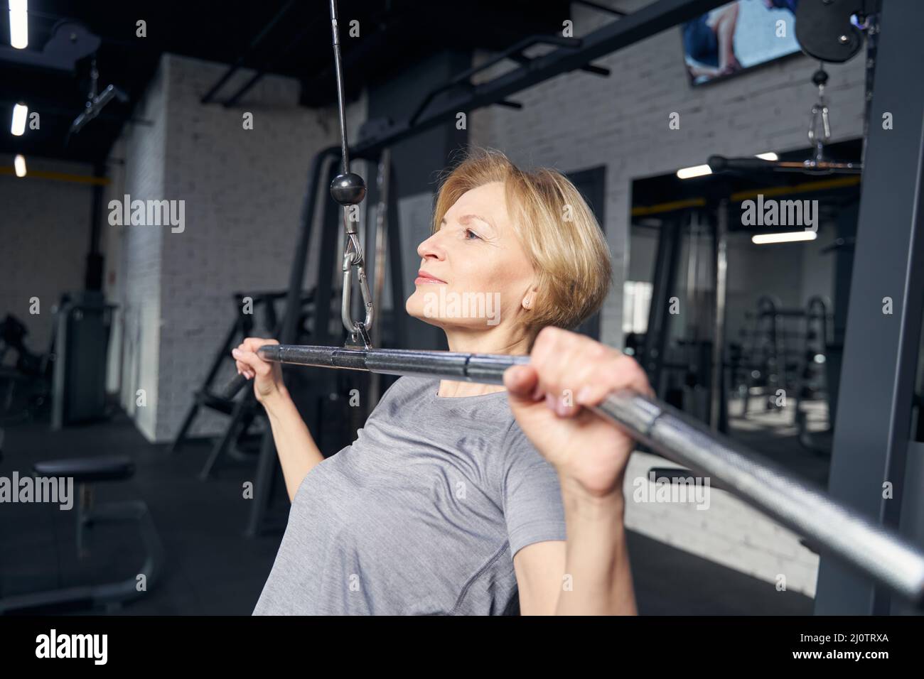 Woman using lat pulldown machine in gym Stock Photo - Alamy