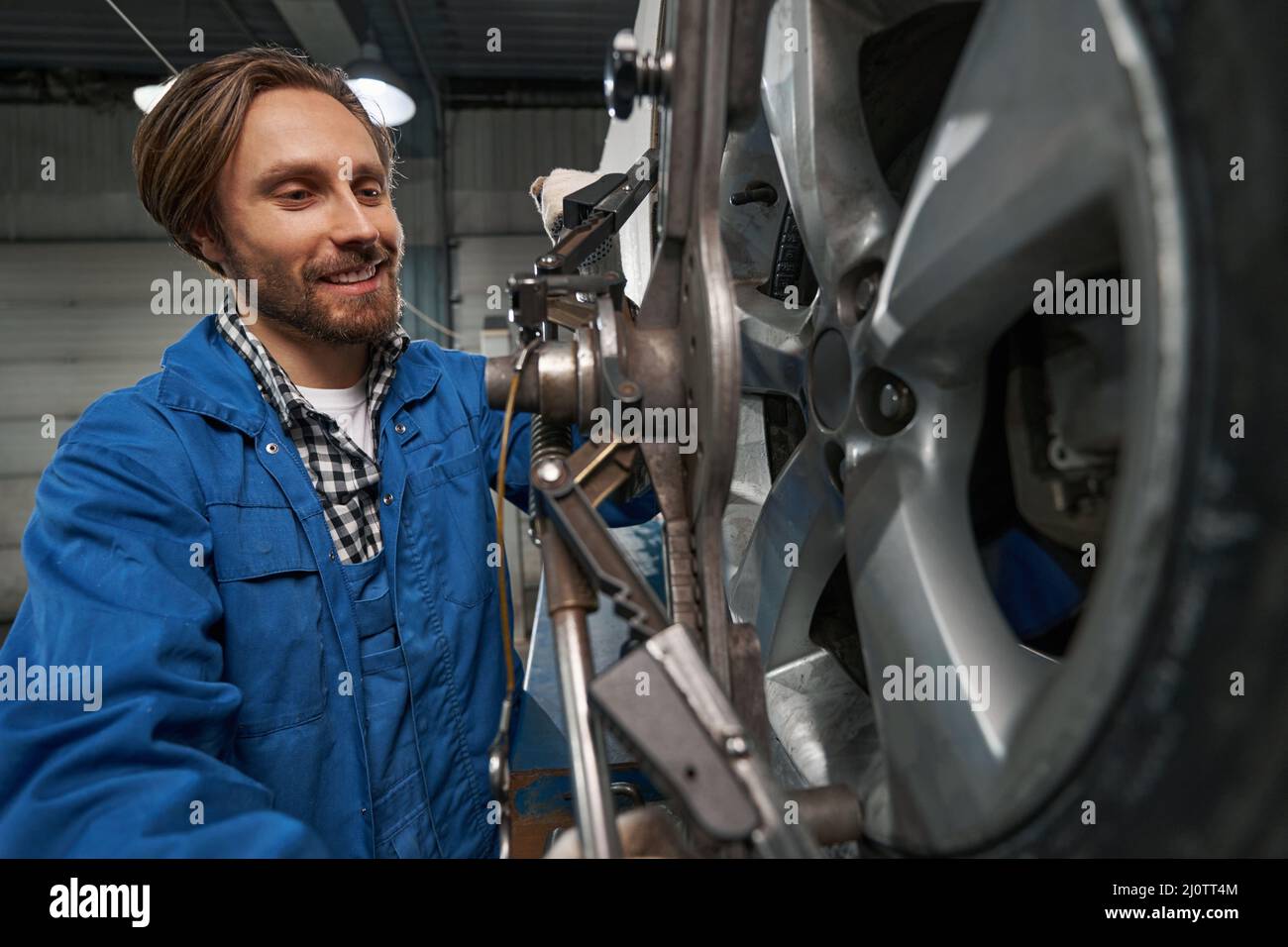 Smiling mechanic performing car maintenance at service station Stock ...