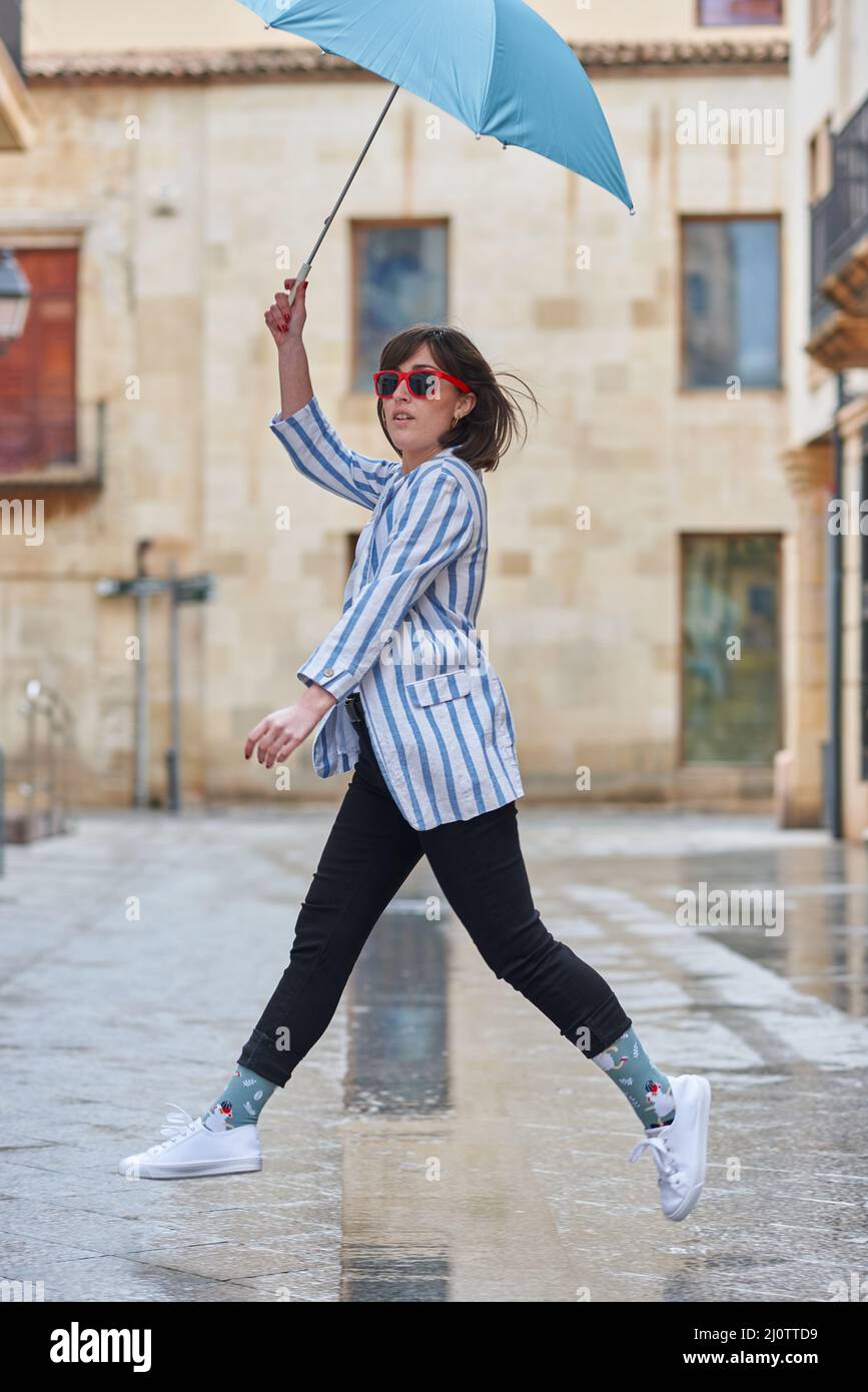 Woman jumping over a puddle on a rainy day Stock Photo - Alamy