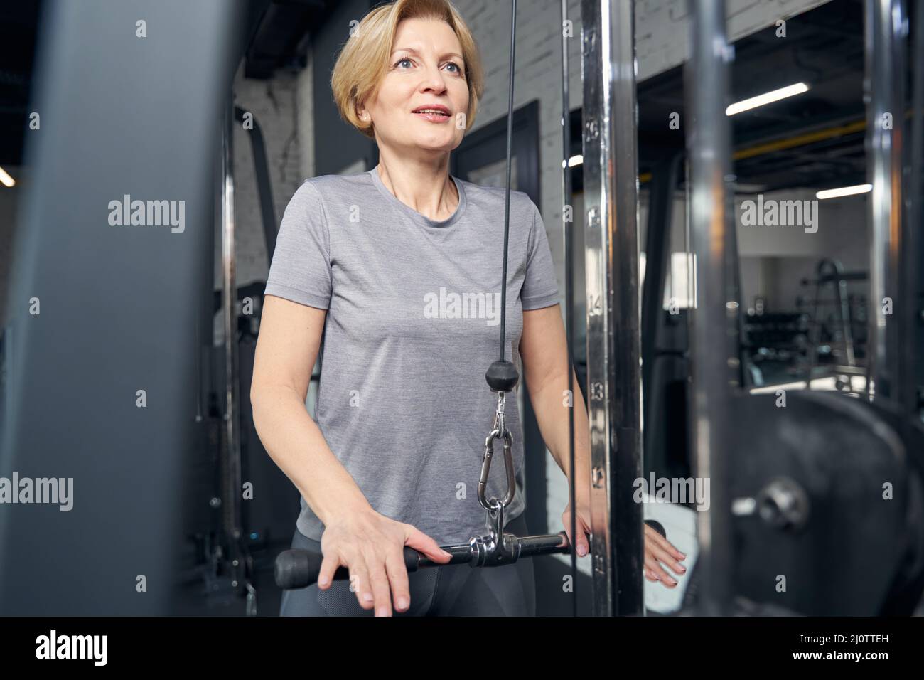 Sporty woman using gym equipment during strength workout Stock Photo ...