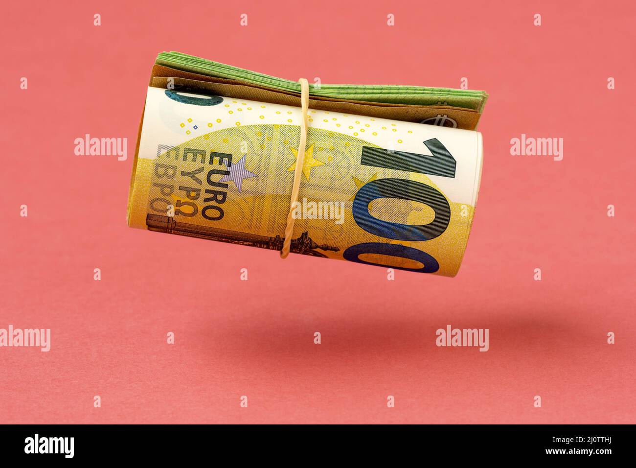 Roll of euro currency levitating over pink background Stock Photo - Alamy