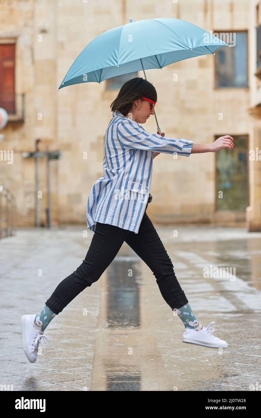 Woman jumping over a puddle on a rainy day Stock Photo - Alamy