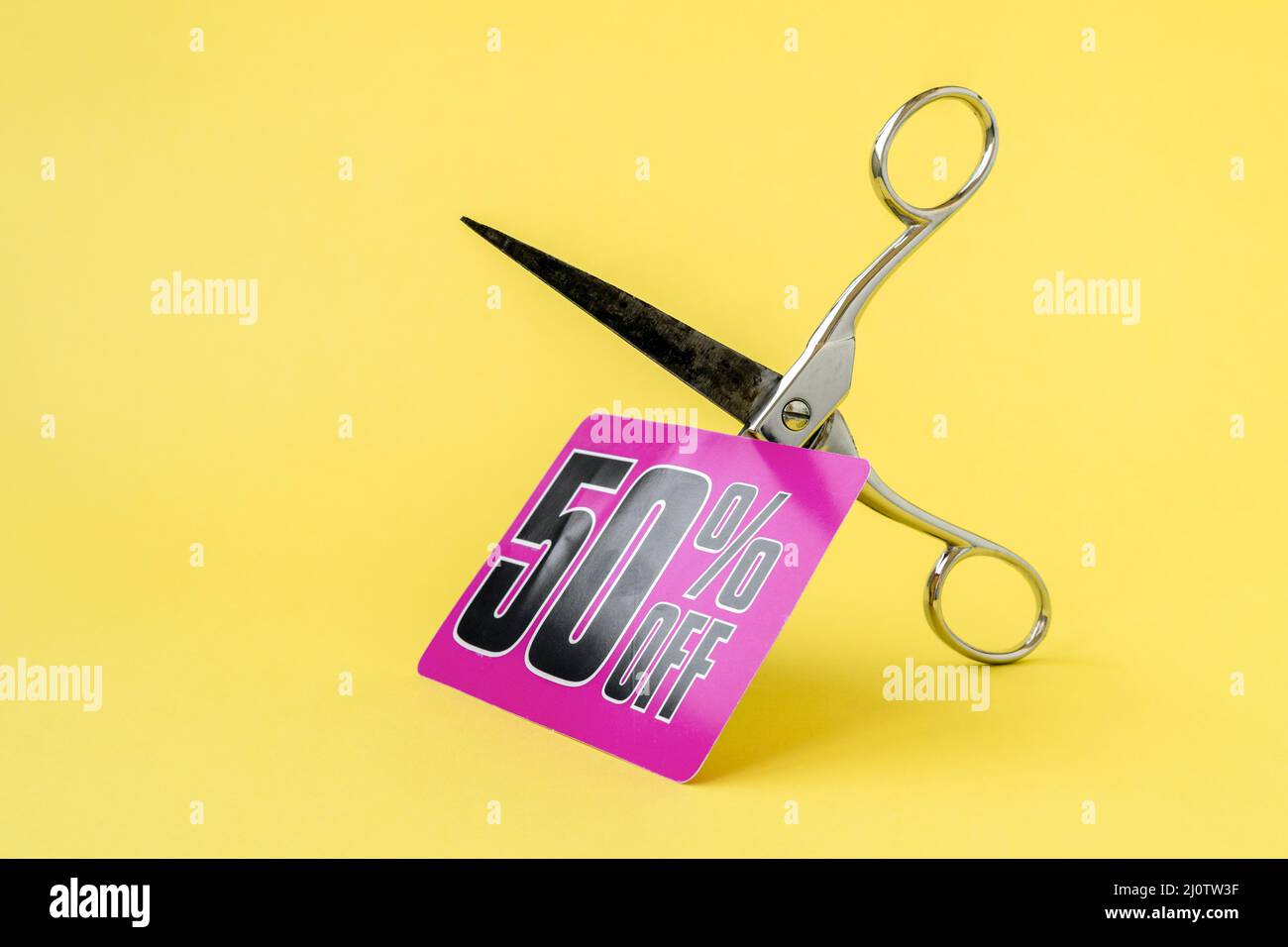 Metal scissors cutting the price tag Stock Photo - Alamy