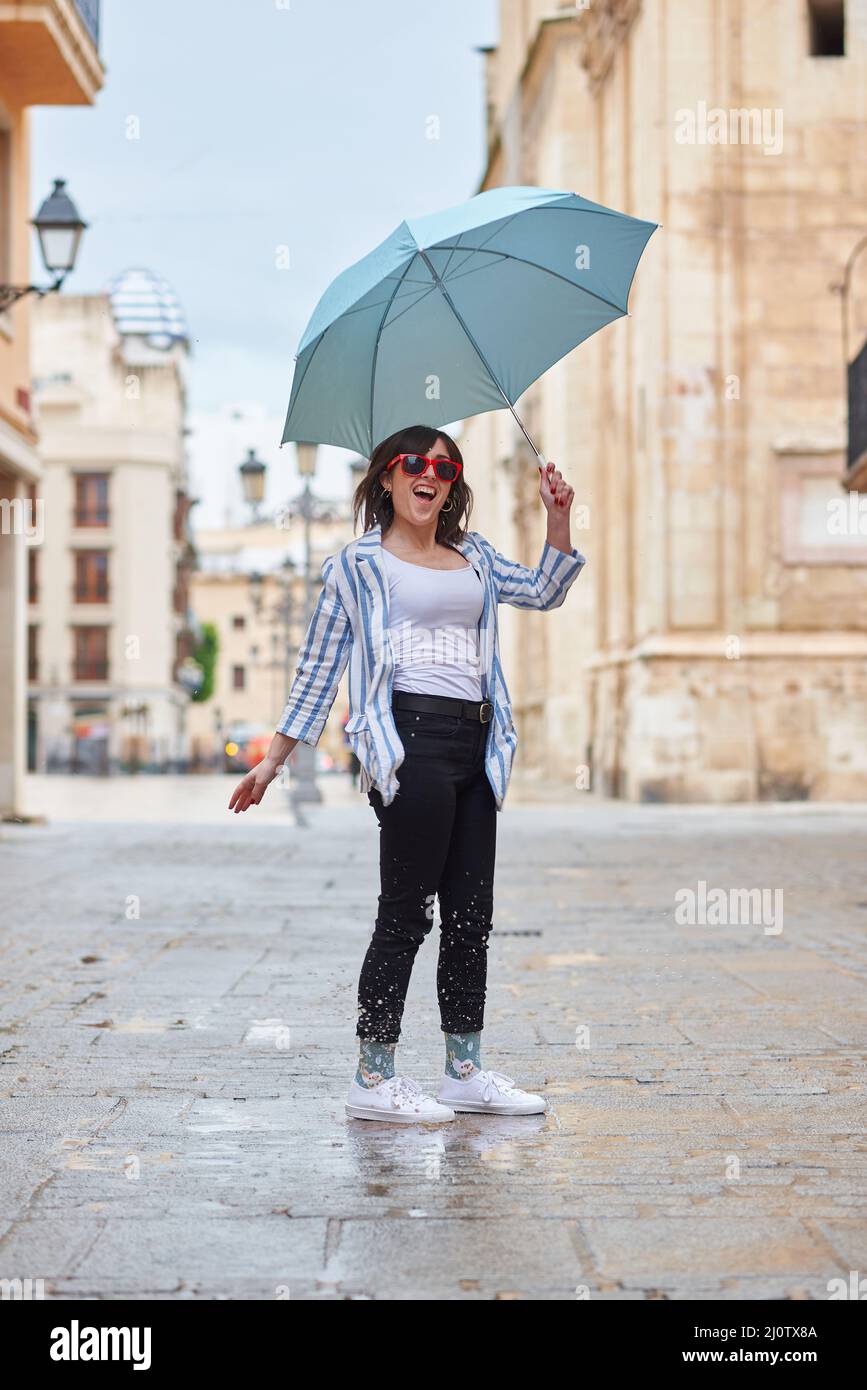 Woman jumping over a puddle on a rainy day Stock Photo - Alamy