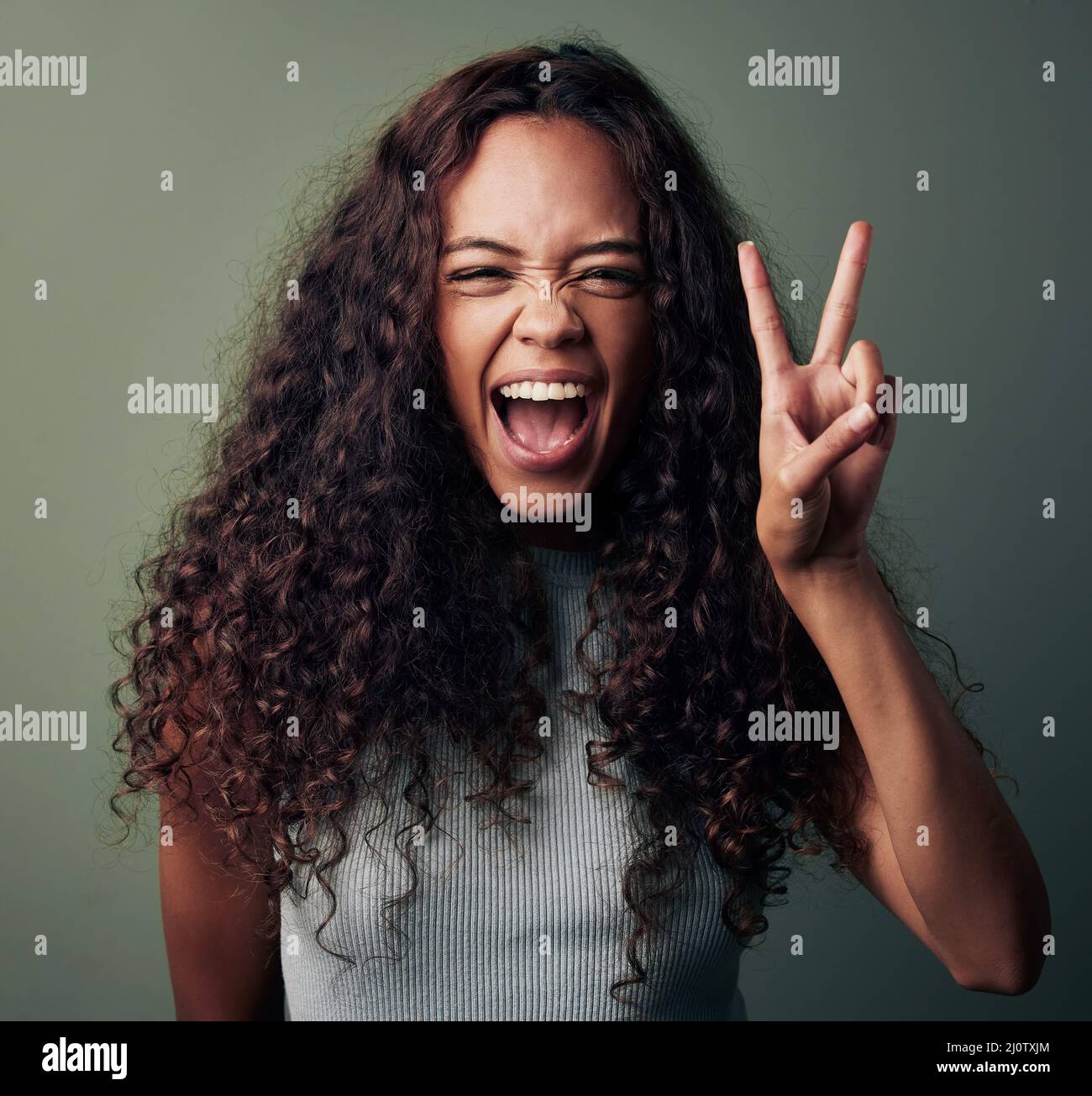 Lets make peace go viral. Studio shot of a young woman making a peace ...
