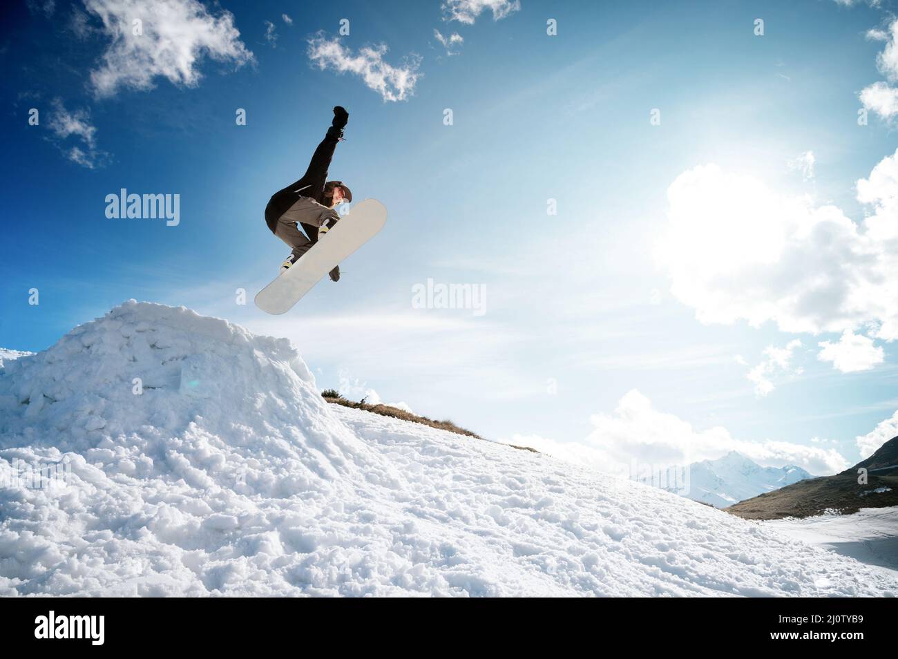 Stylish young girl snowboarder does the trick in jumping from a snow ...