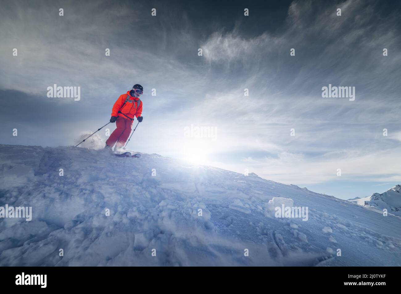 Athlete male skier jumps from a snow-covered slope against the backdrop ...