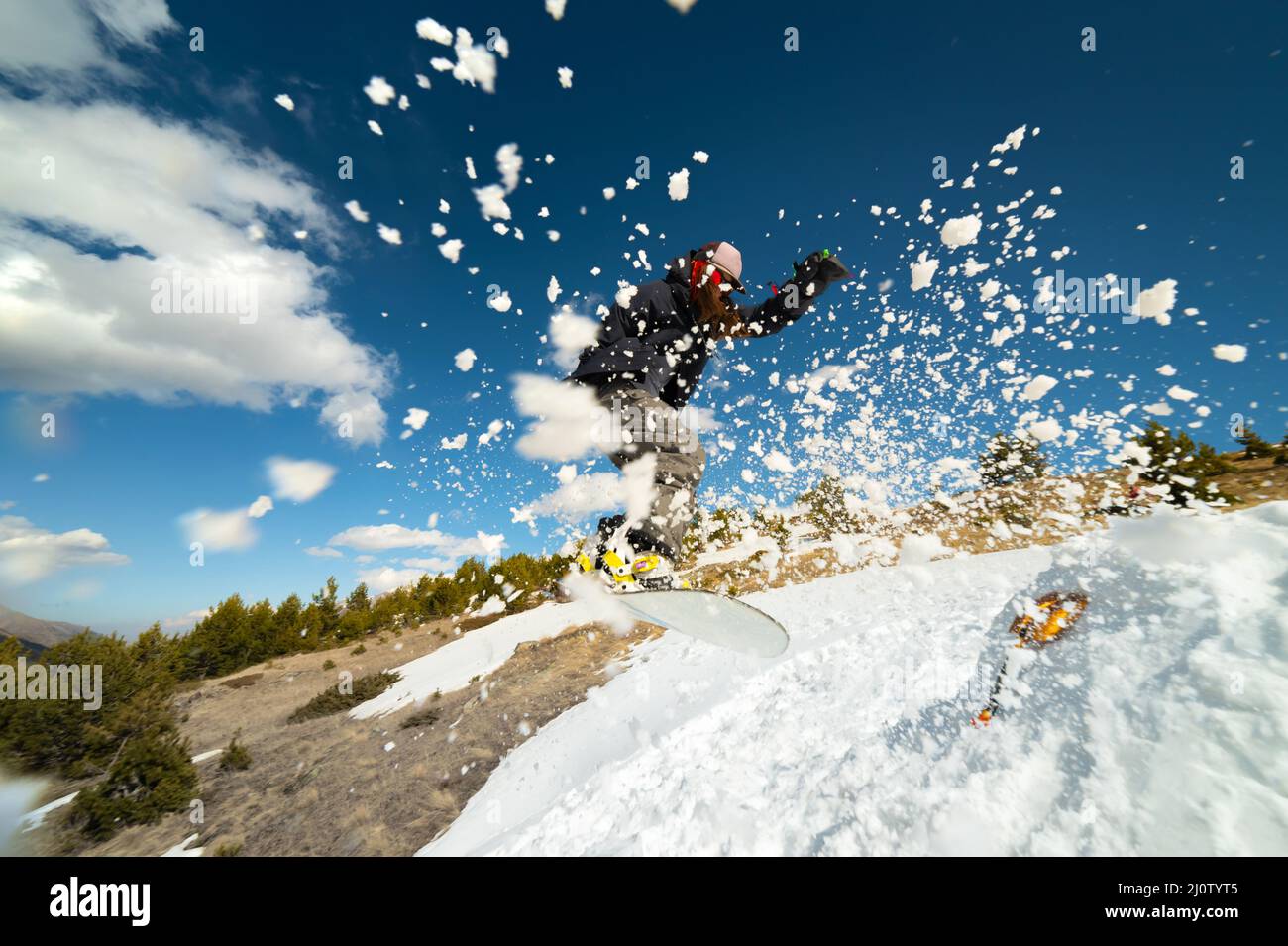 Stylish young girl snowboarder does the trick in jumping from a snow ...