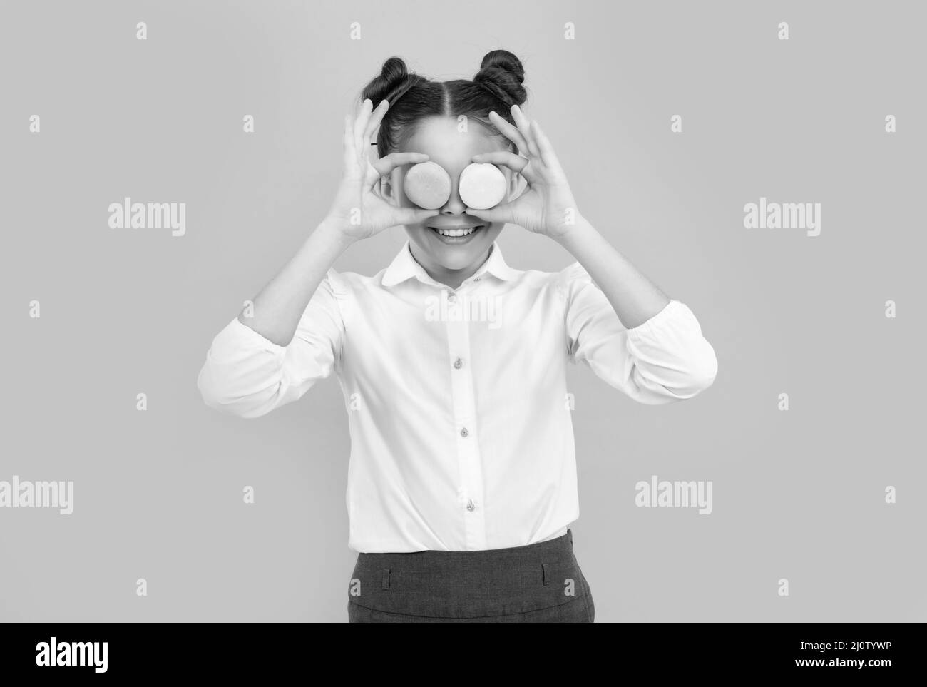 cheerful teen girl wear uniform holding french cookie on blue ...