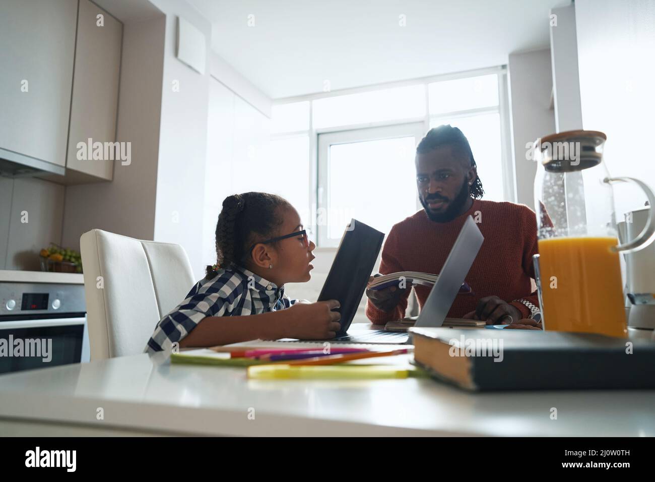 African American man listening intently his young daughter who reading ...