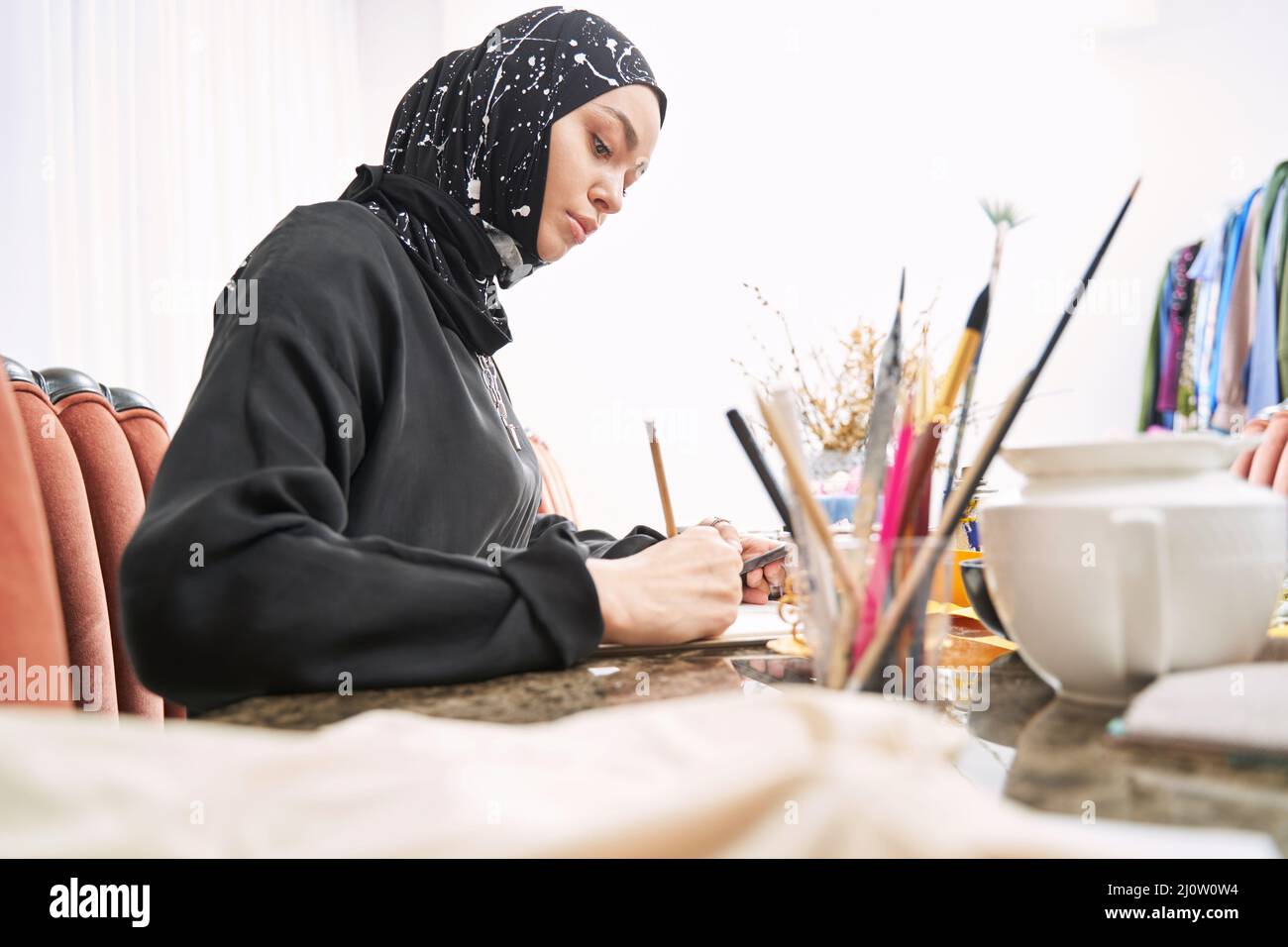 Muslim female designer creating clothes in sketchbook Stock Photo - Alamy