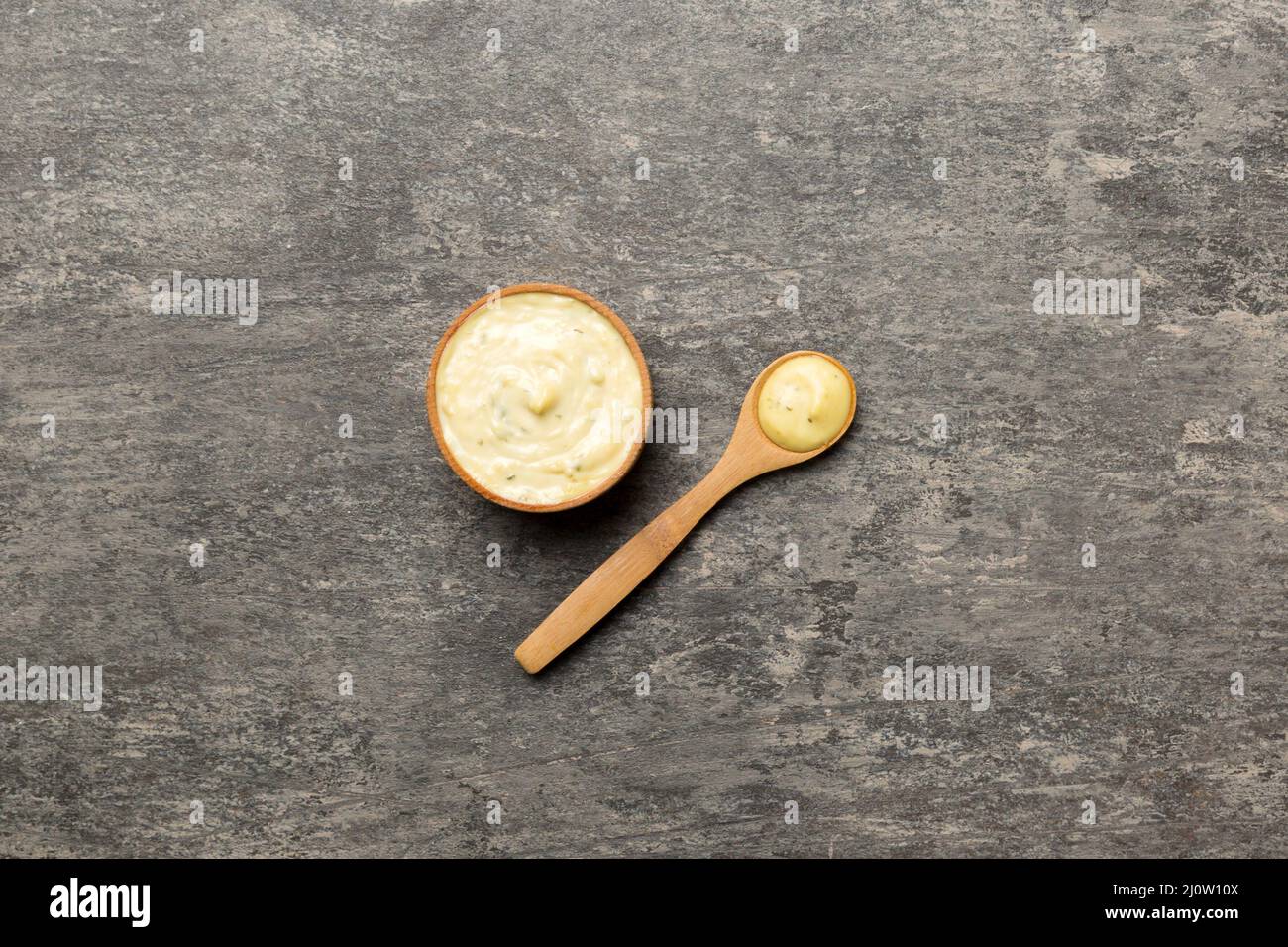 Cheese sauce in wooden bowl with spoon on cement background. Top view ...