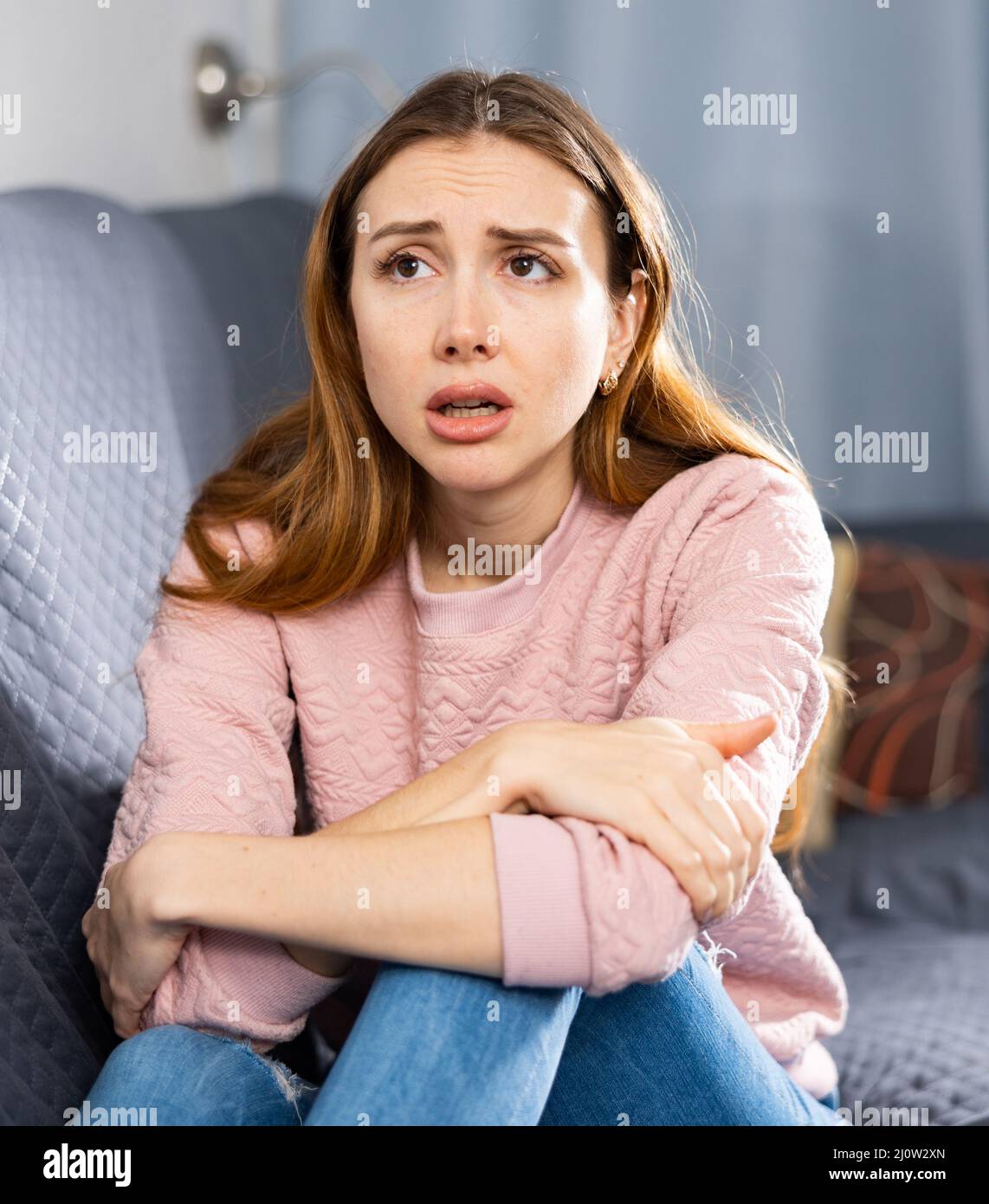 Upset woman crying while sitting on a sofa in room Stock Photo - Alamy