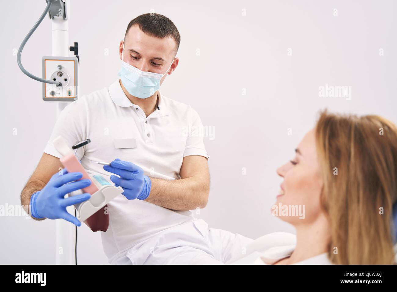 Dentist showing tooth model to woman in dental clinic Stock Photo - Alamy