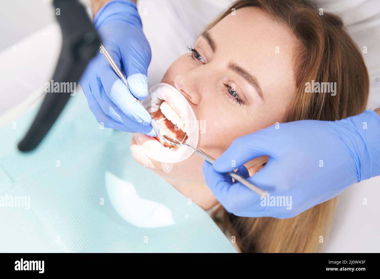Dentist examining woman teeth with dental instruments in clinic Stock ...