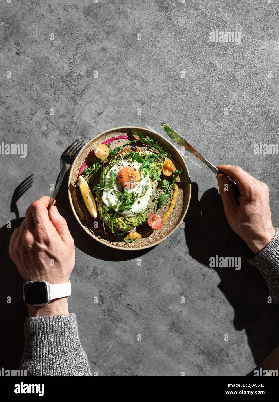 Top view of a male hands with fork and knife to eat omelette with ...