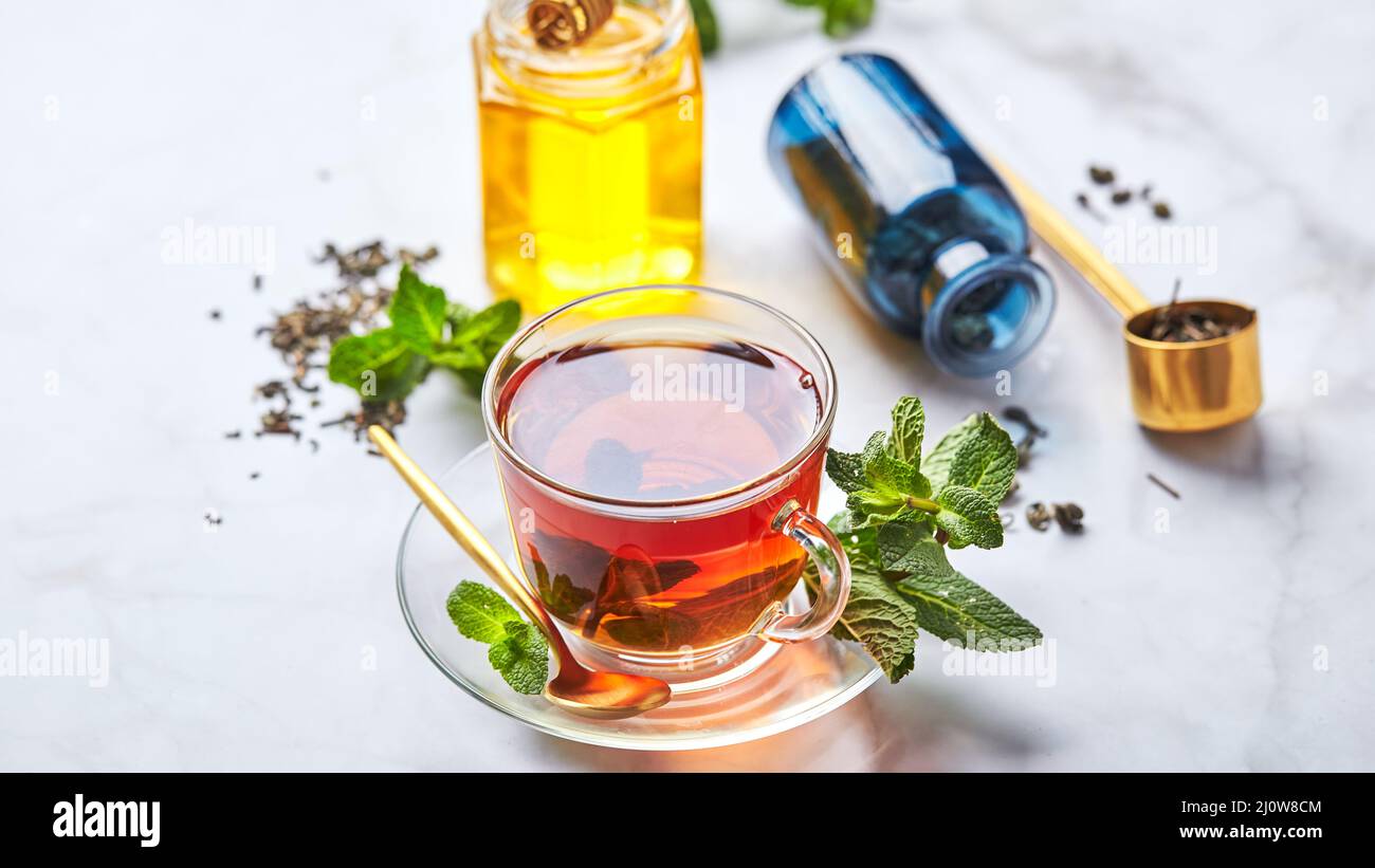 Black tea in glass transparent mug with mint leaves and honey. Calming ...