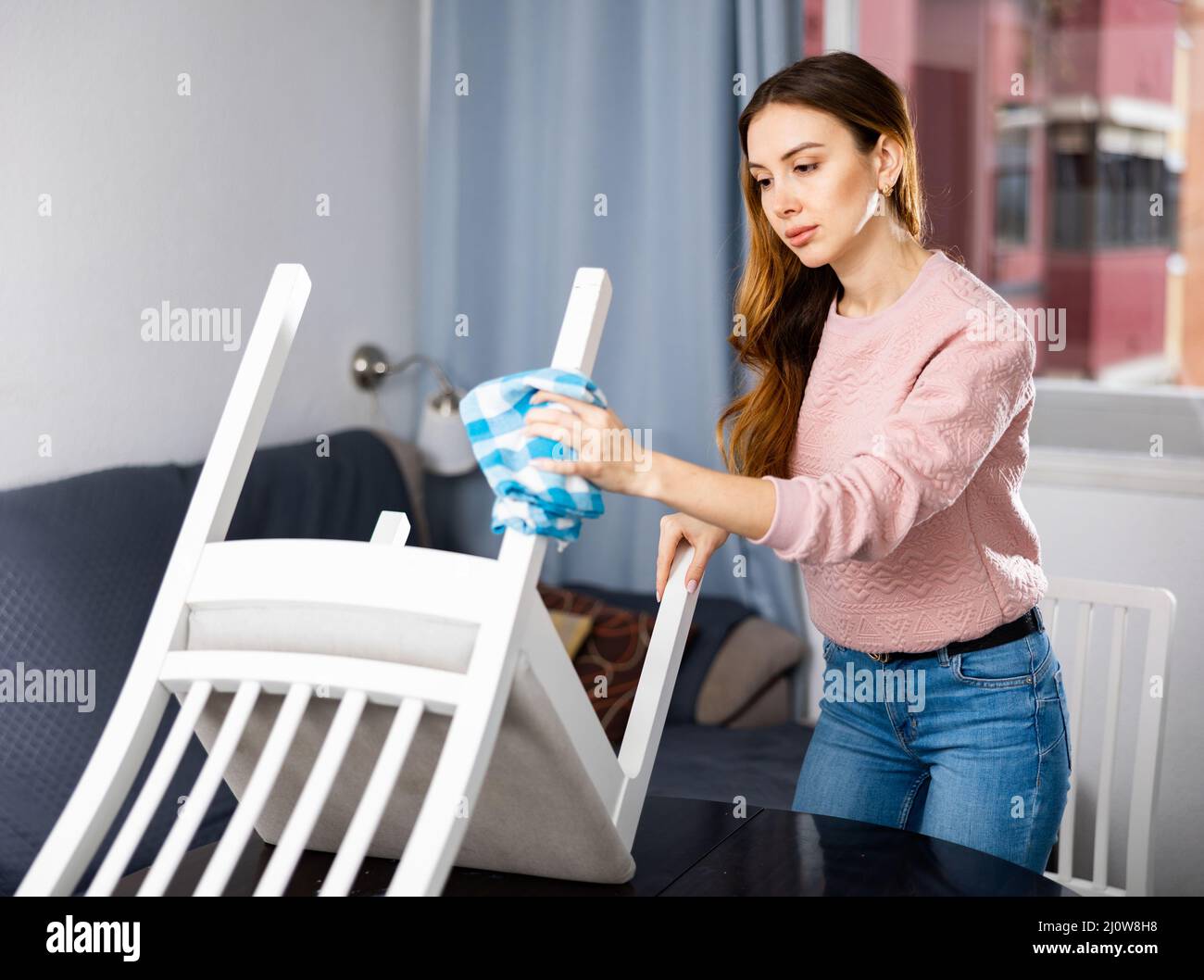 Young woman wipes a chair with a damp cloth Stock Photo - Alamy