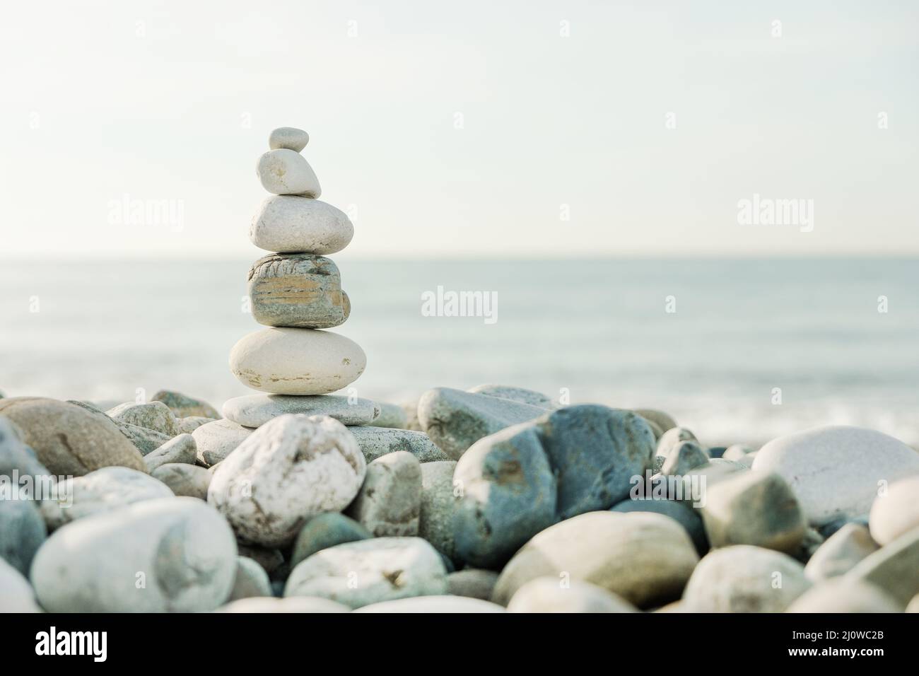 Zen pyramid of balanced stones on a background of the sea and blue sky ...