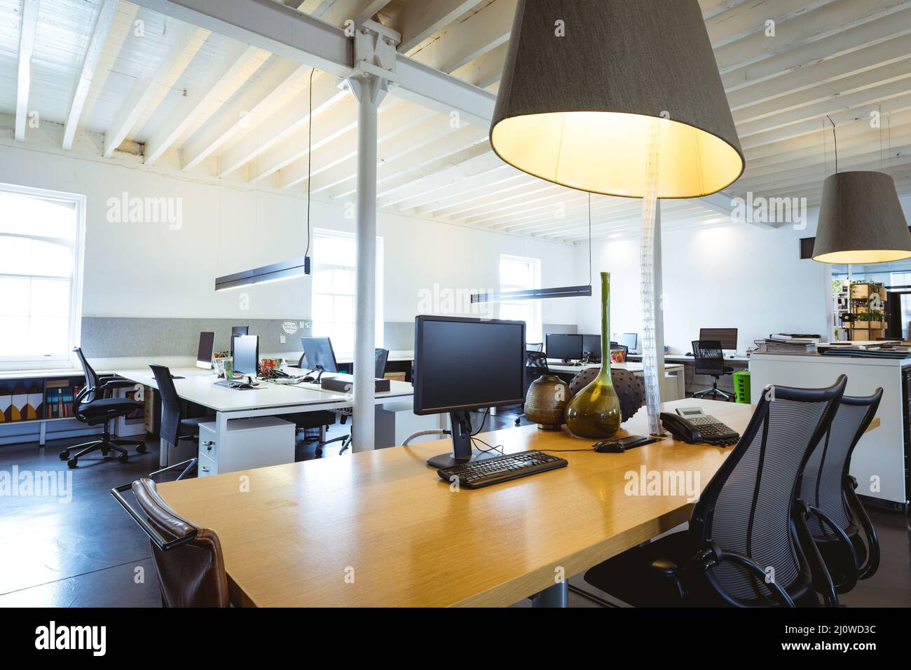 Illuminated pendant light over desk with computers in modern office ...