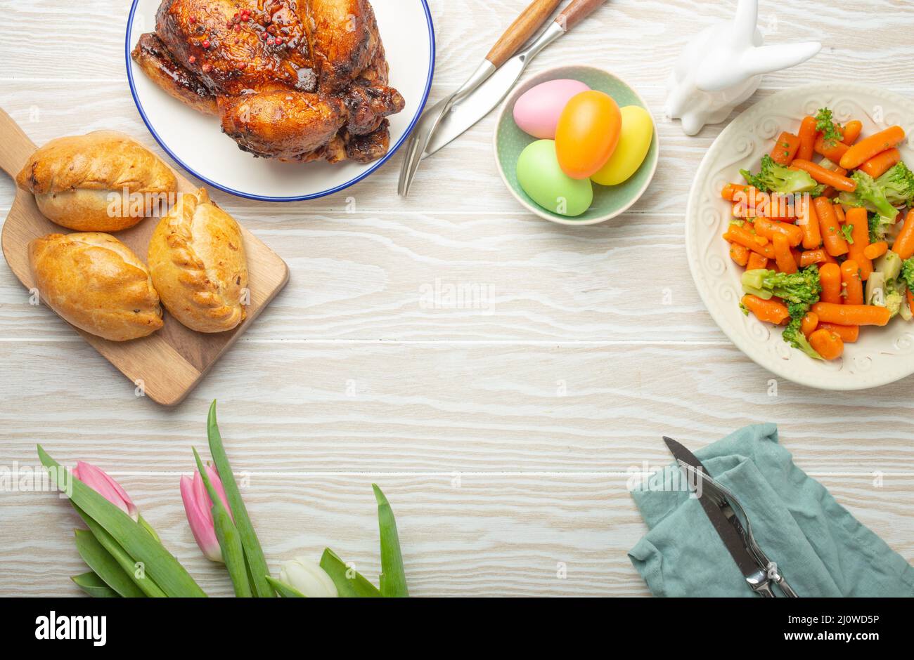 Easter food on white rustic table: pastel colored eggs, roasted chicken ...