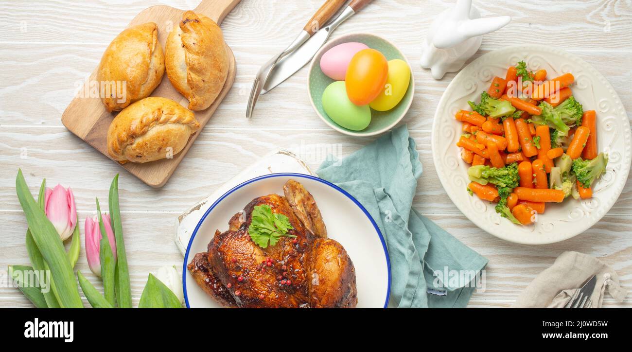 Easter food on white rustic table: colored eggs, roasted chicken ...