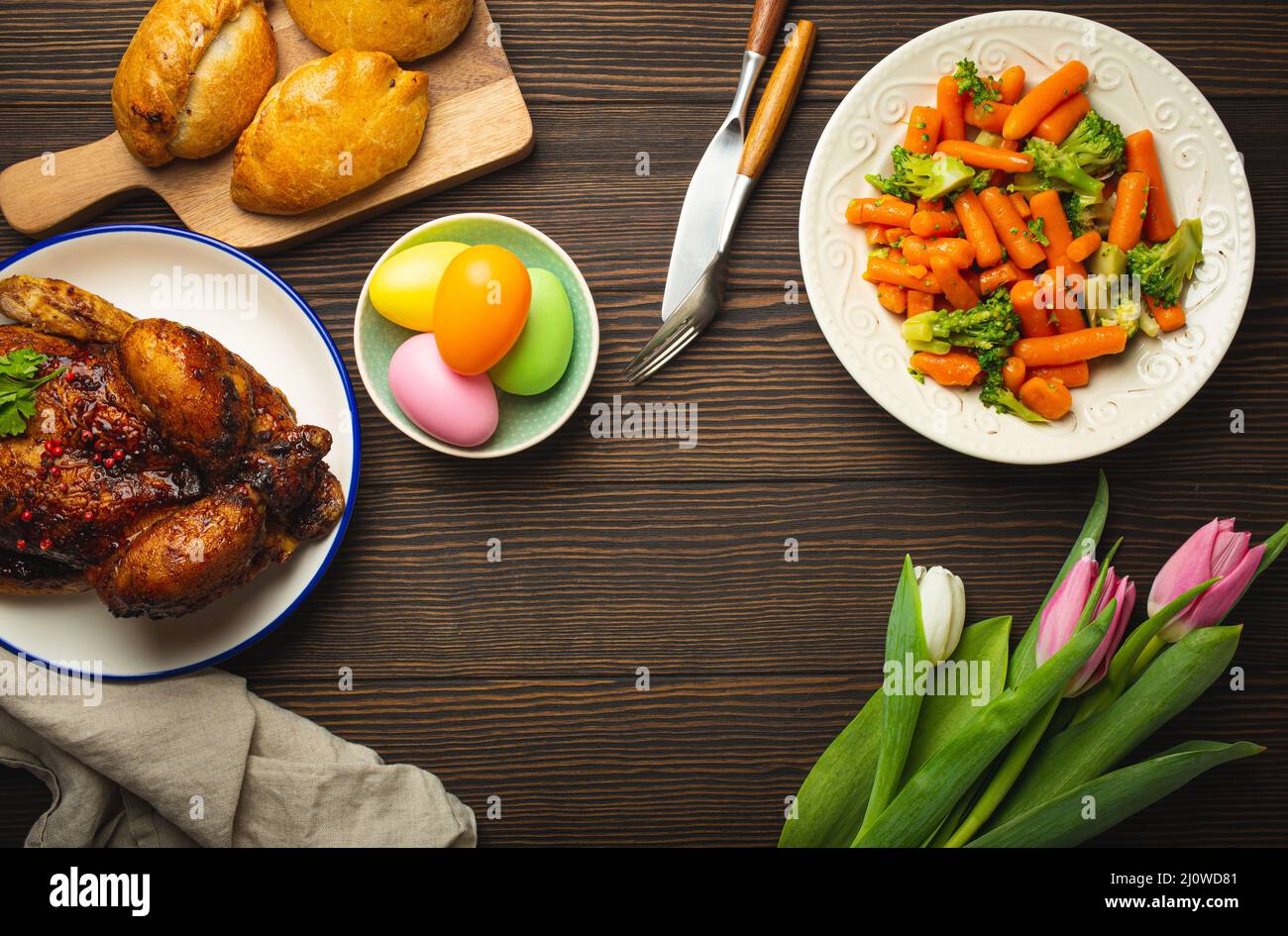 Easter food on dark rustic table: pastel colored eggs, roasted chicken ...