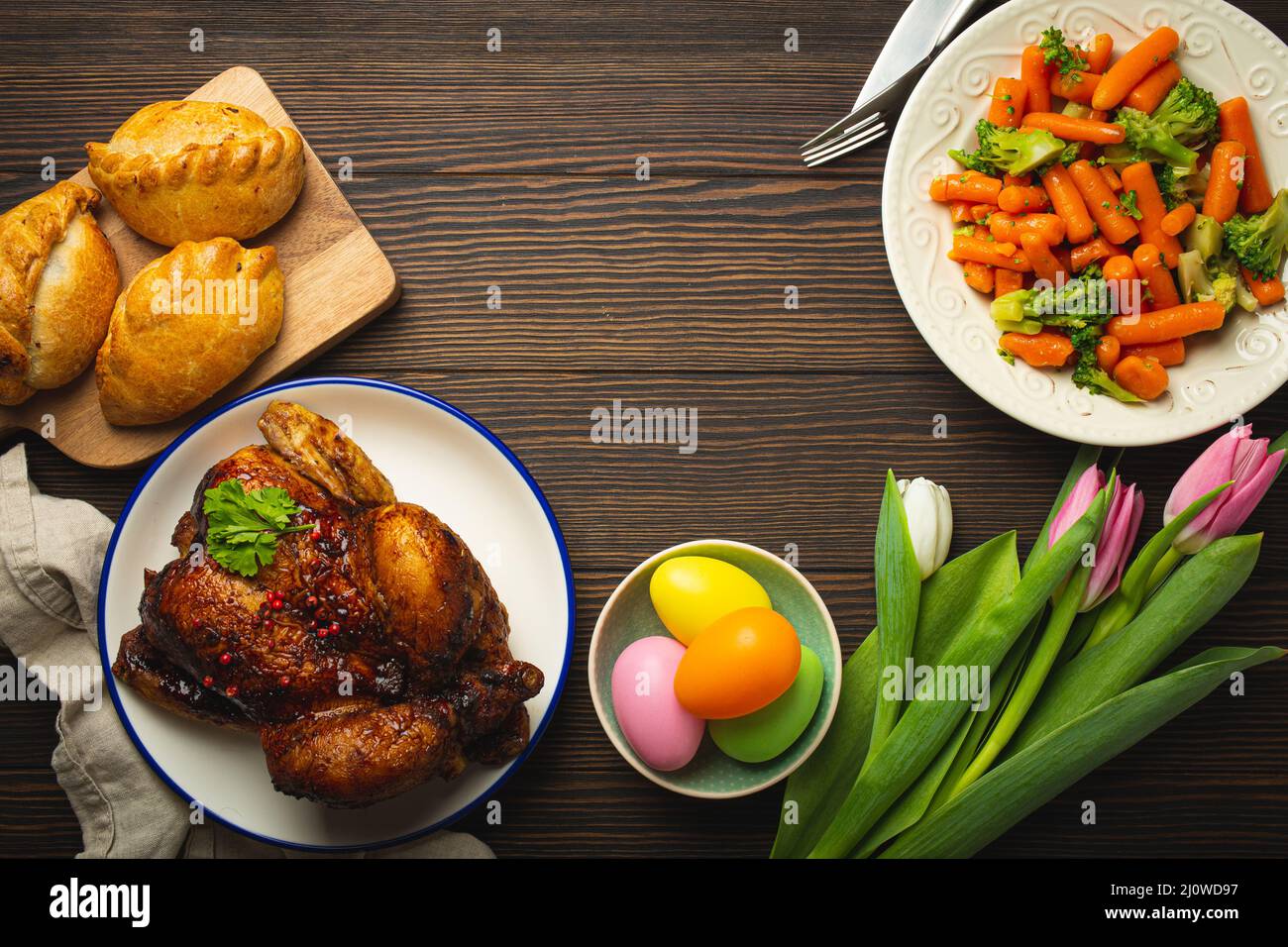 Easter food on dark rustic table: pastel colored eggs, roasted chicken ...