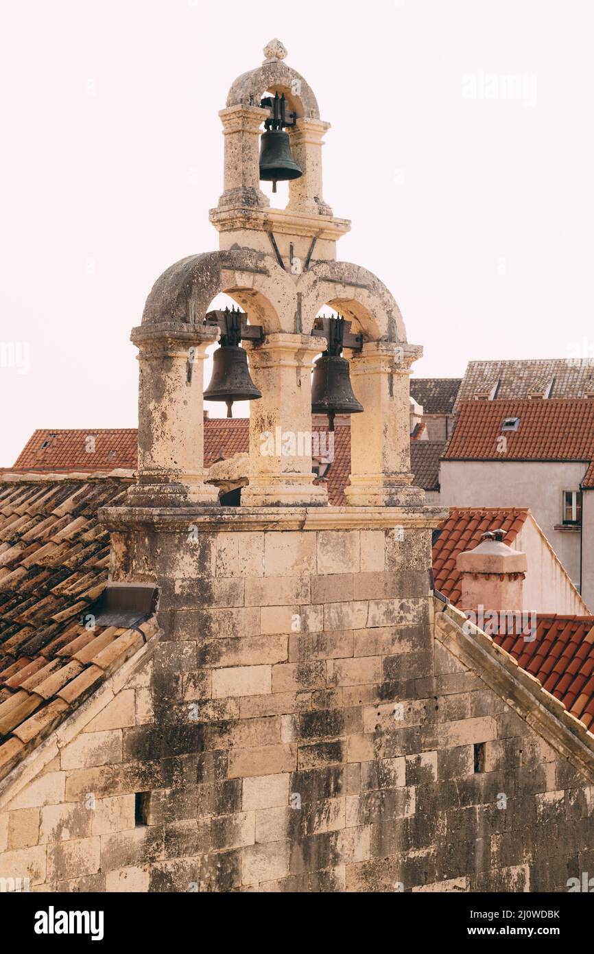 Three bells on an old stone bell tower against a background of tiled ...
