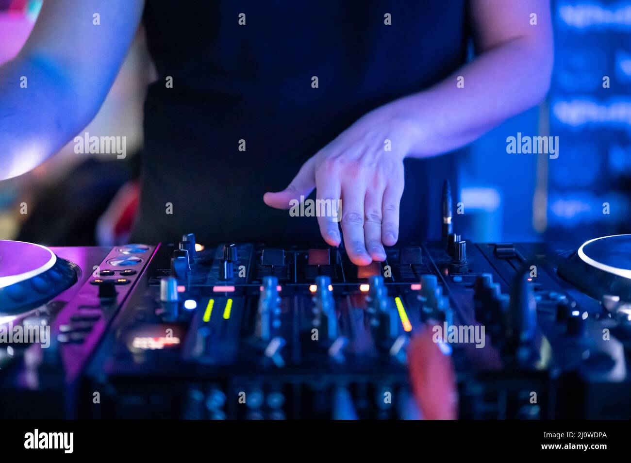Close up Front view of of DJ hands controlling a music table in a night ...