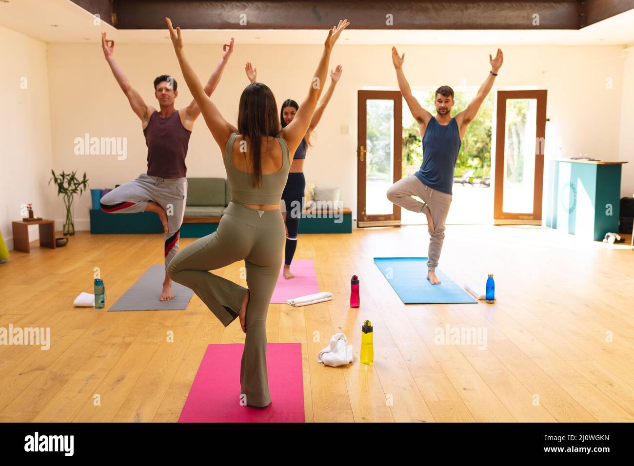 Female instructor showing yoga exercise to multiracial men and woman in ...
