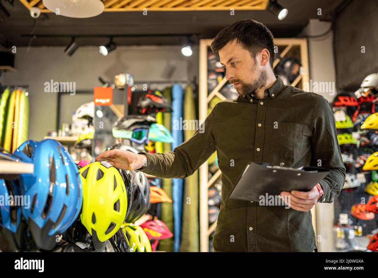 A male bike shop manager makes an inventory of sports helmets in a bike ...