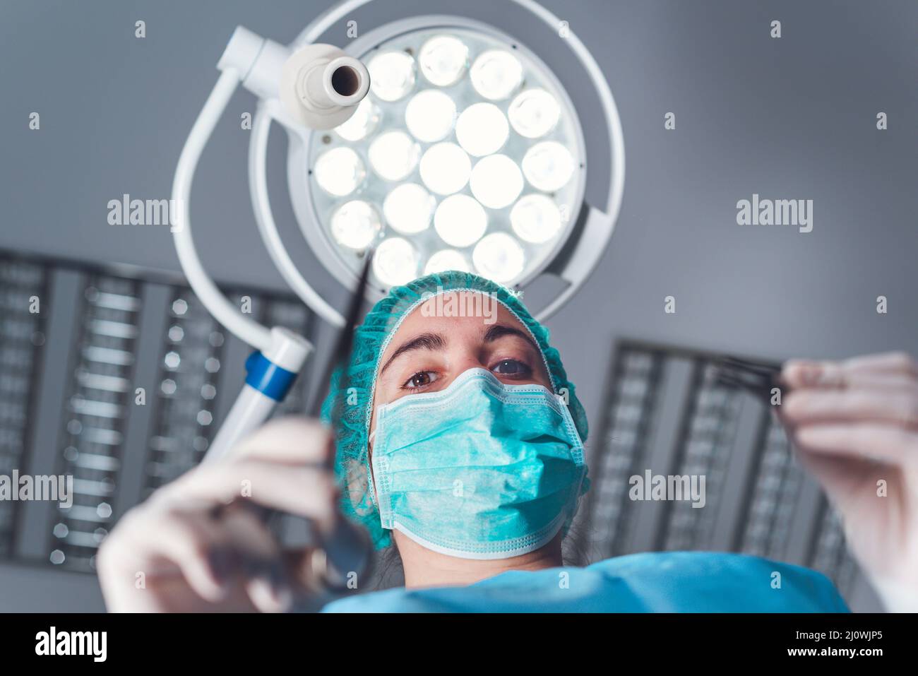 From below woman surgeon in medical uniform using professional tools ...