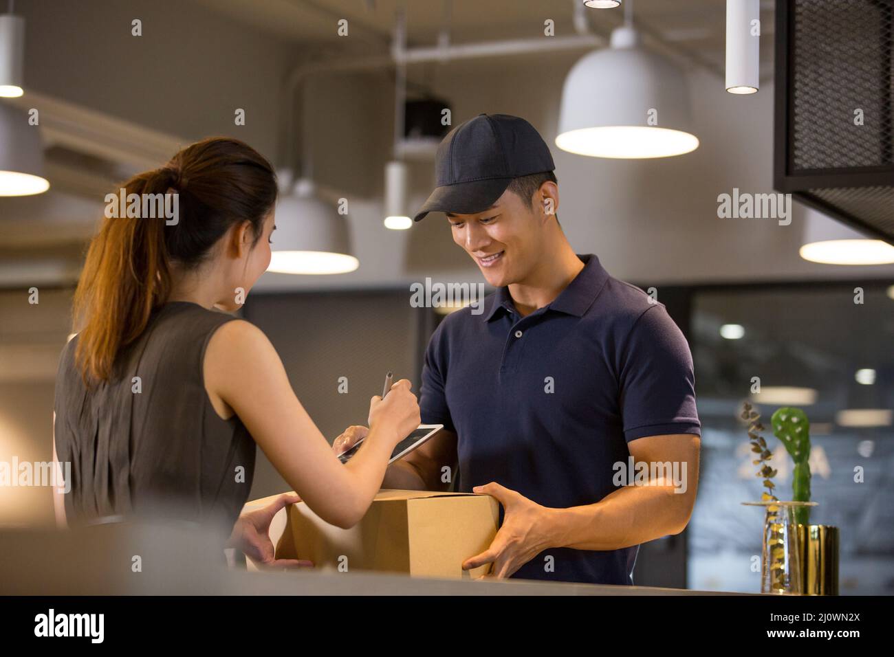Chinese receptionist signing for delivery in office Stock Photo - Alamy
