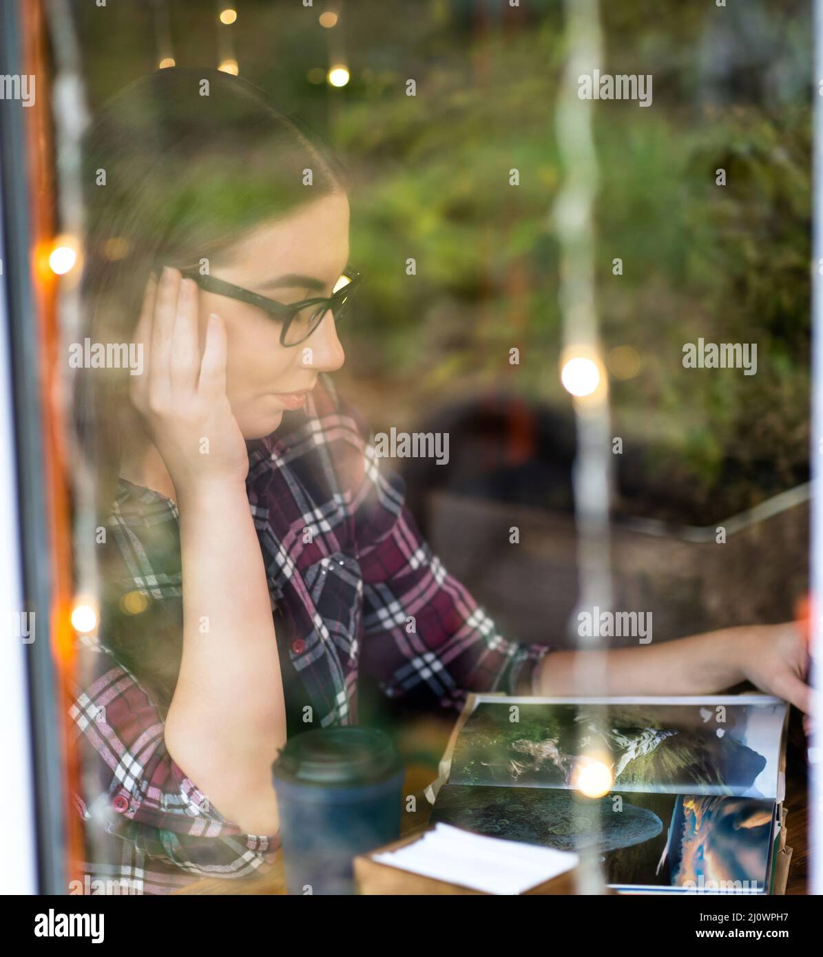 Pretty student girl spend time reading books in a cafe with lights ...
