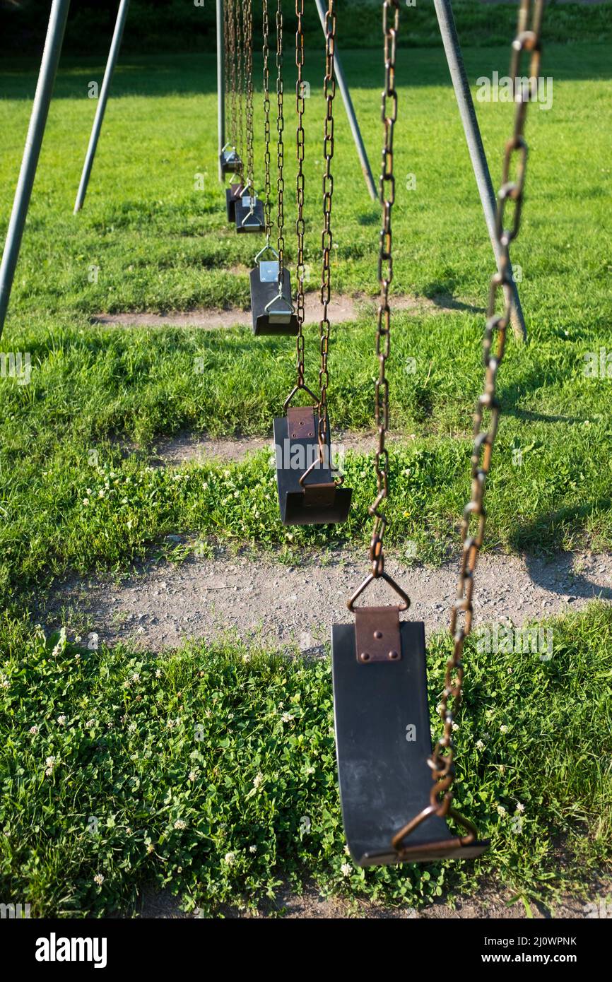 Row of empty child's swing set seats Stock Photo - Alamy