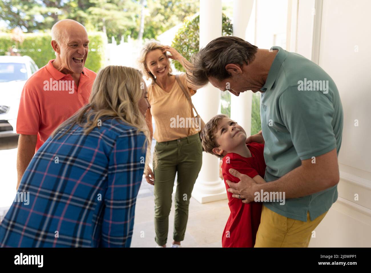 Caucasian couple welcoming their family at the entrance of the house ...