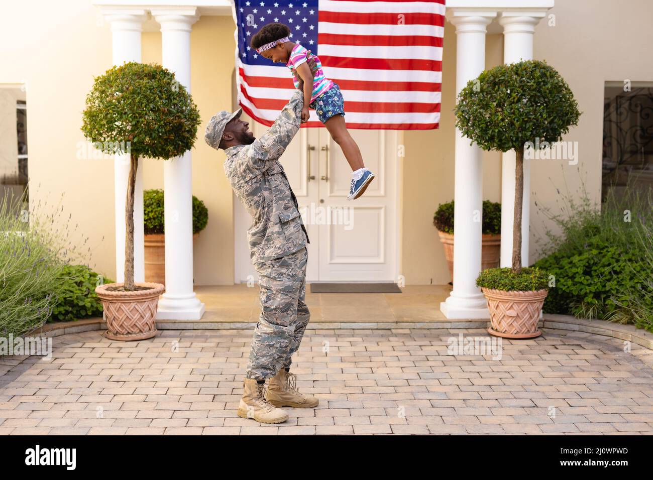 Happy african american military father holding aloft daughter in front ...