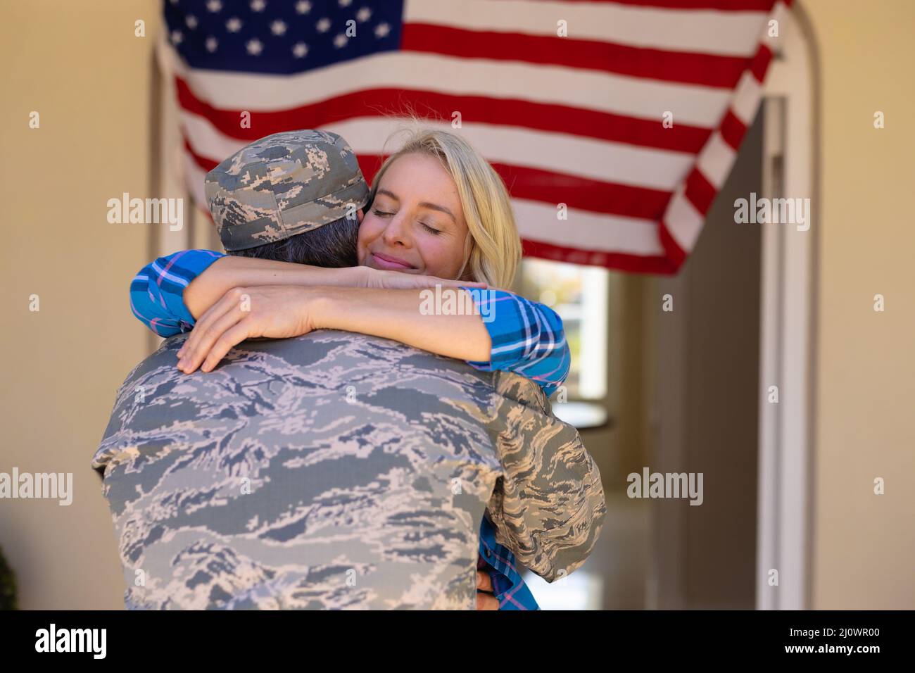 Happy blond caucasian woman hugging army soldier on his return home at ...