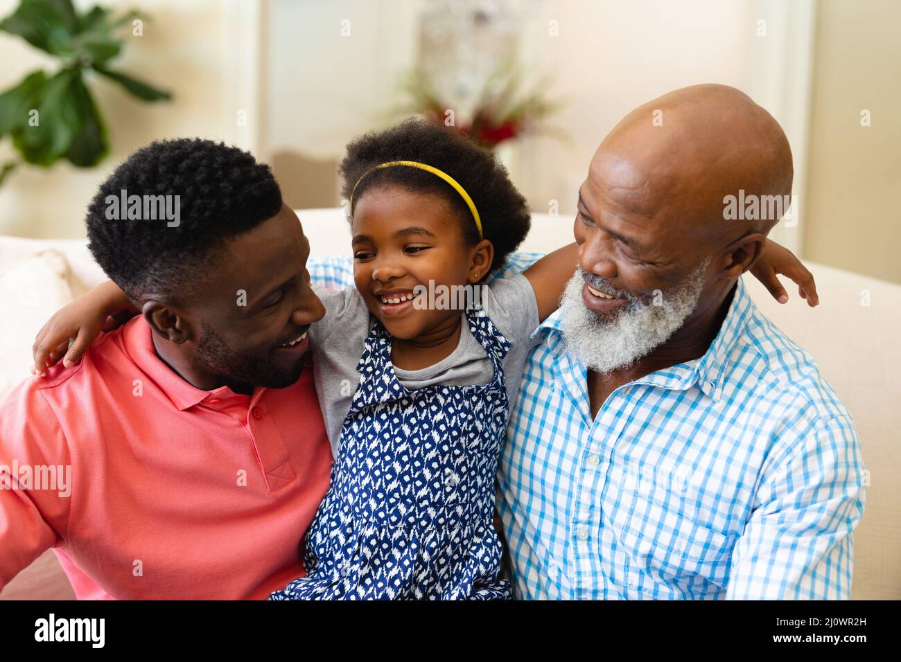 African american grandfather, father and granddaughter smiling looking ...