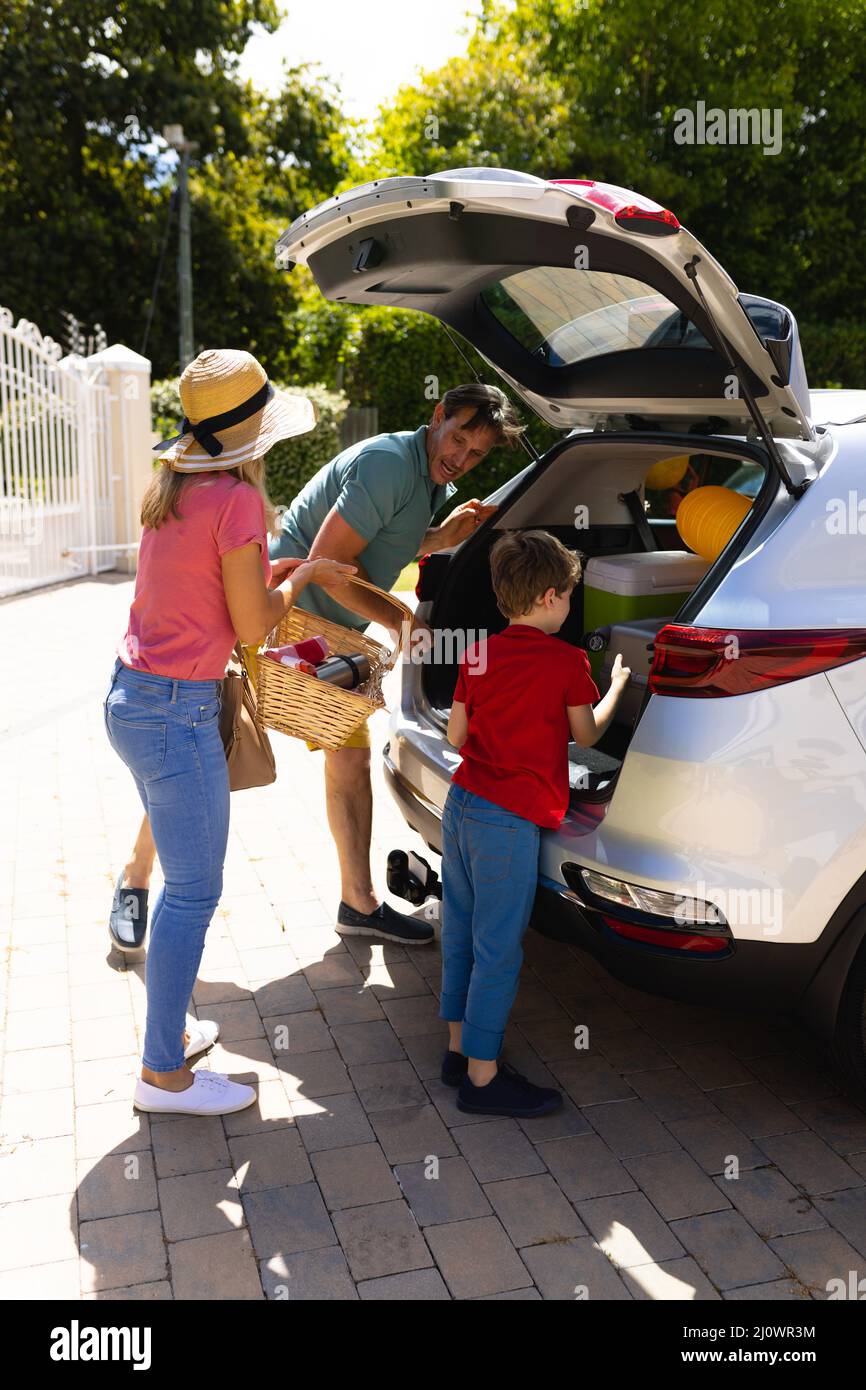 Happy caucasian family loading their luggage in their car outdoors ...