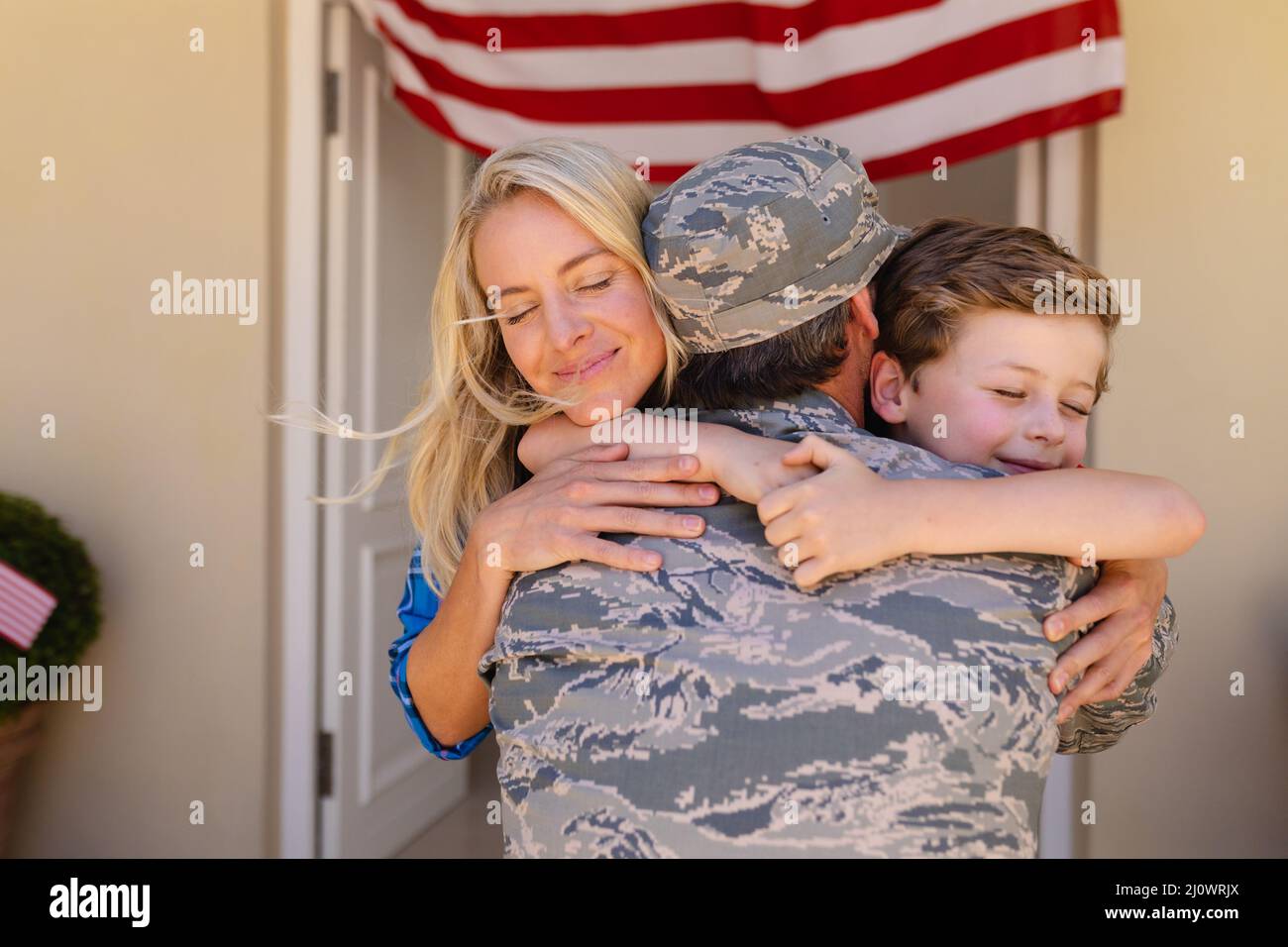 Caucasian woman and son hugging military man on his return home at ...