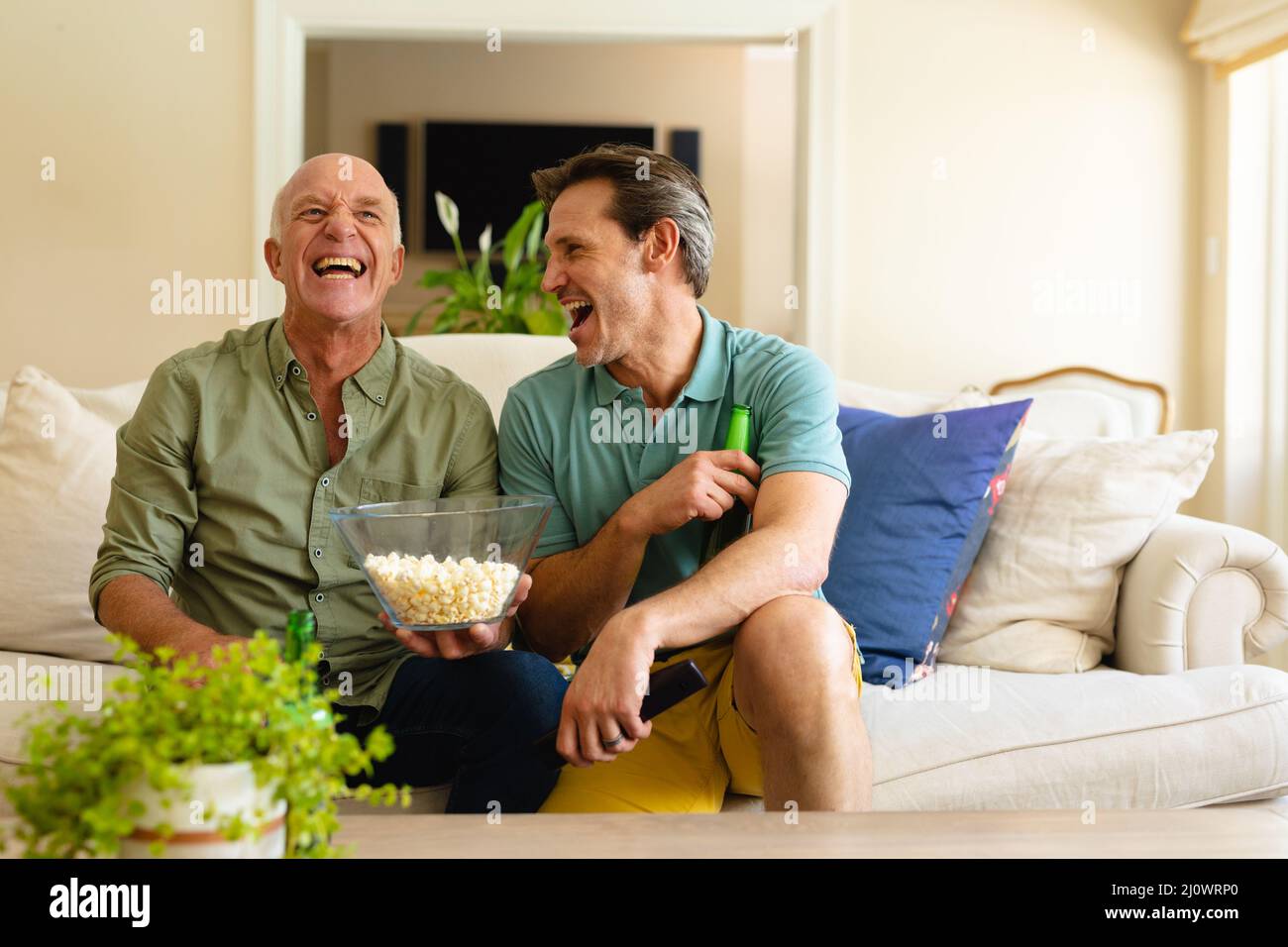Caucasian Father And Son With Beer And Popcorn Watching Tv Sitting