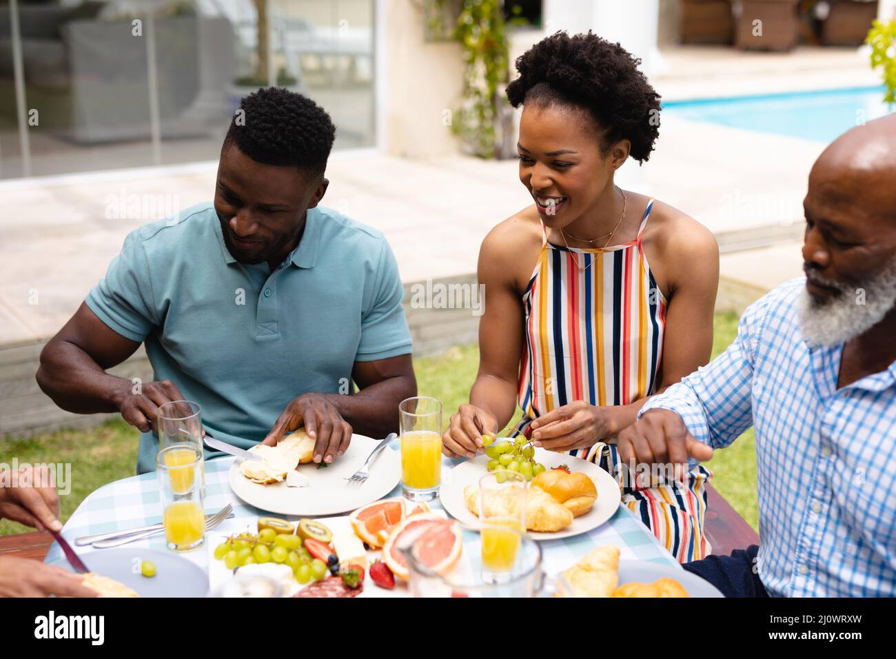 African american family eating brunch at dining table in backyard Stock ...