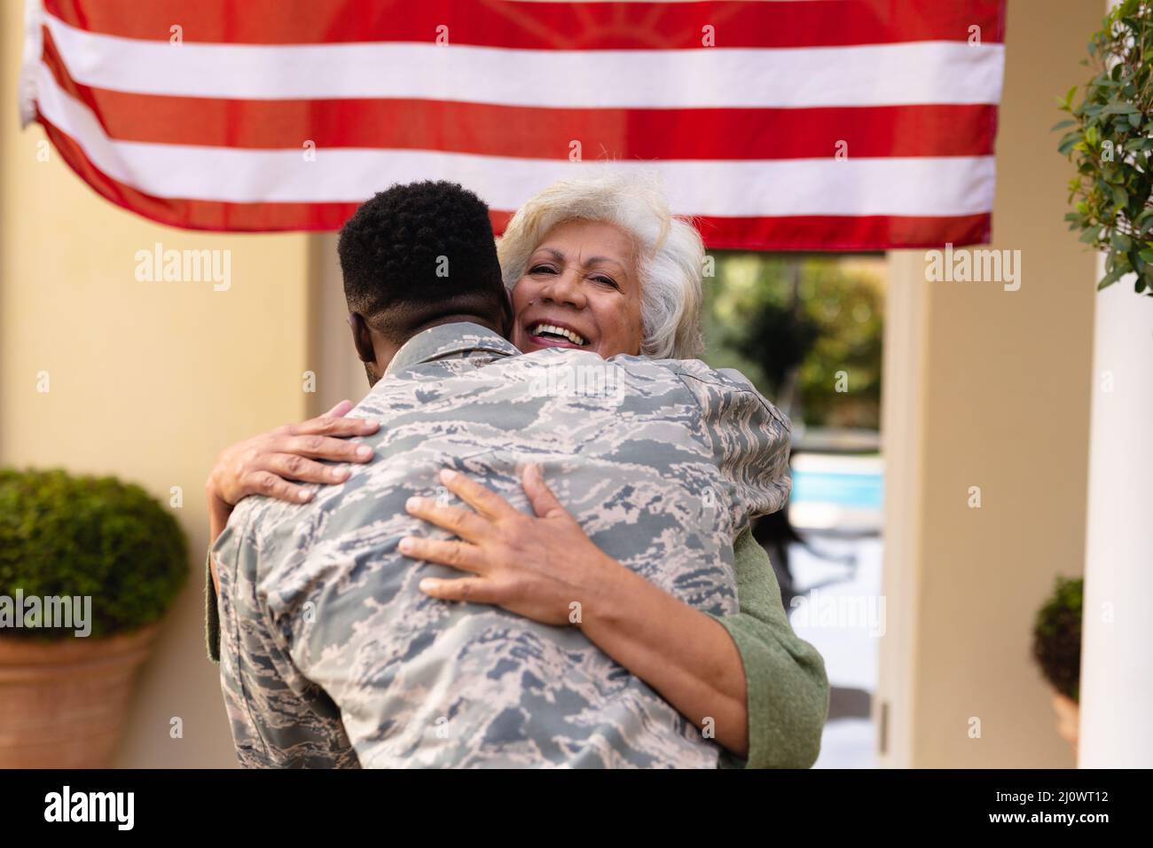 Happy senior african american woman embracing soldier son on his return ...