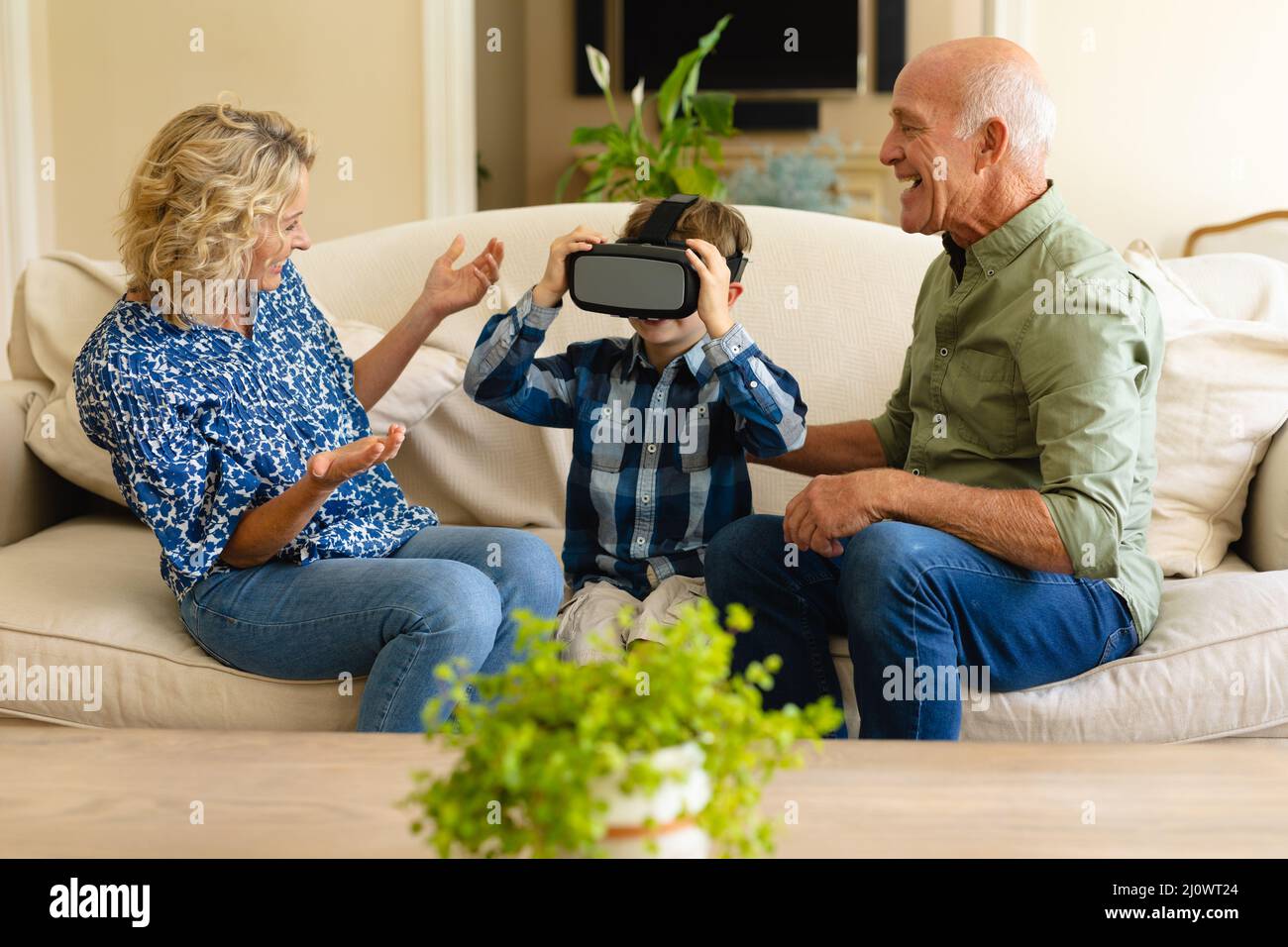 Caucasian grandson wearing a vr headset while grandparents watching ...
