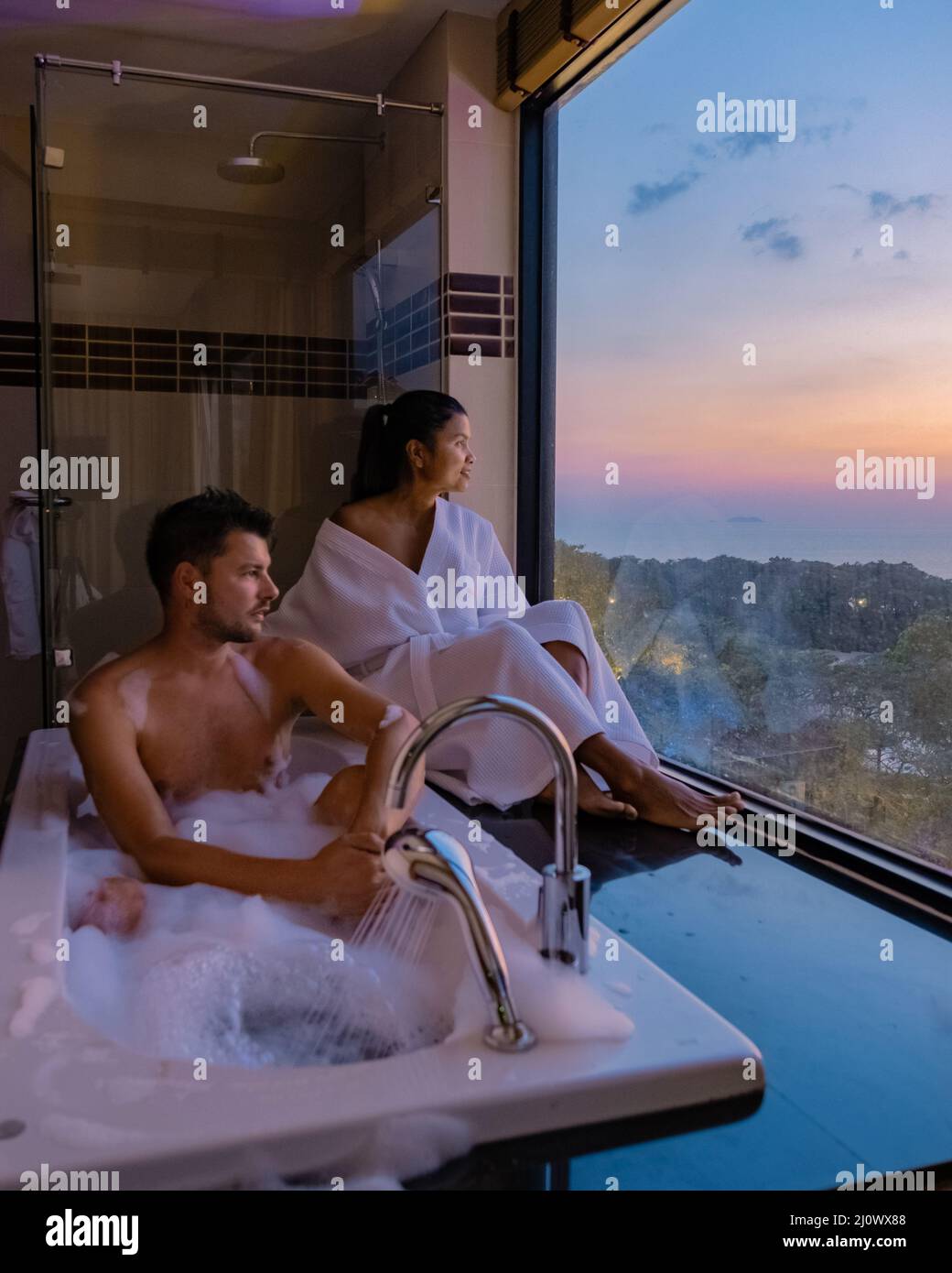 Couple man and woman in bathroom taking a bath during sunrise ...
