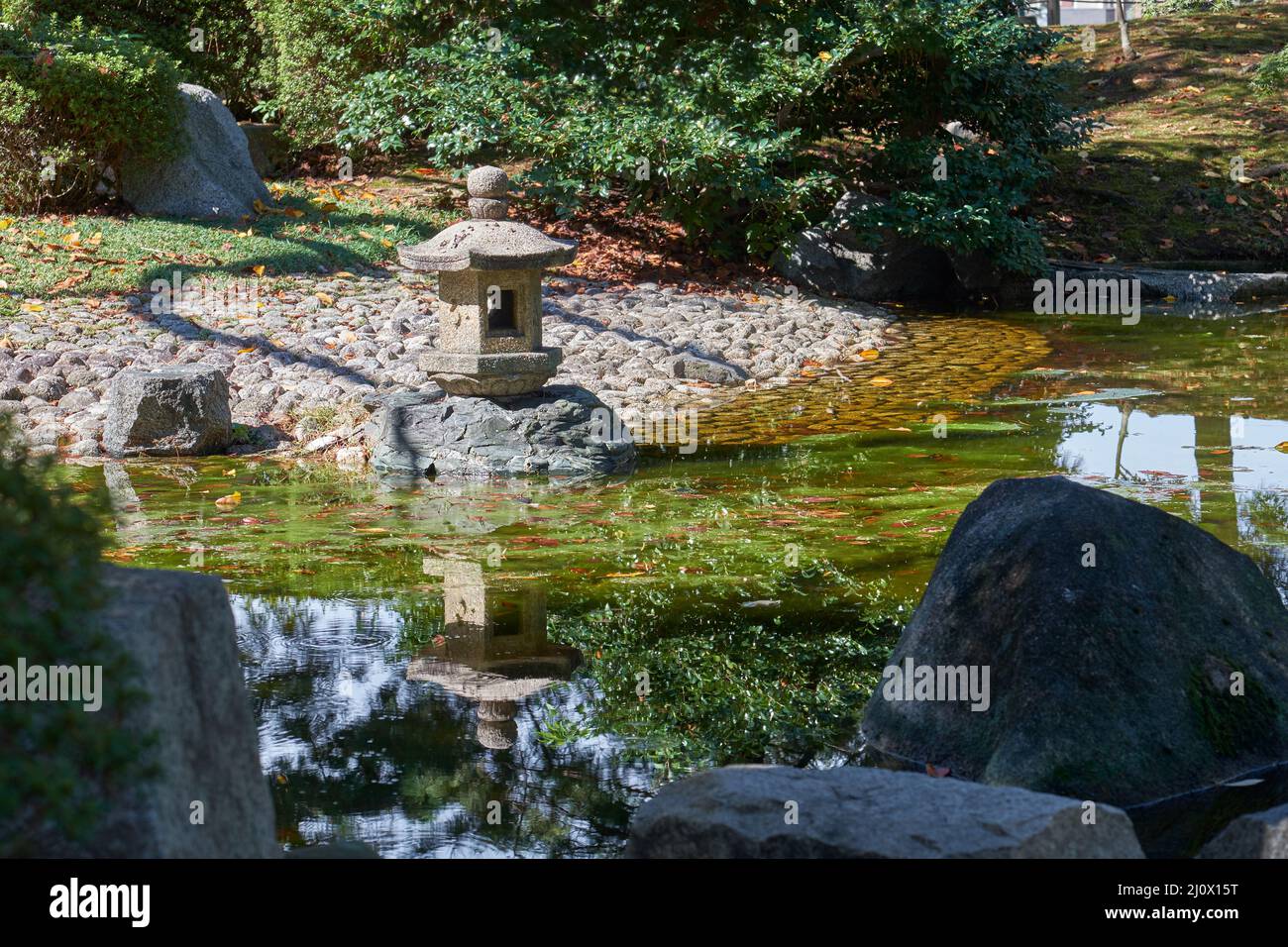 Traditional stone toro lantern on the edge of the pond at the Nagoya ...