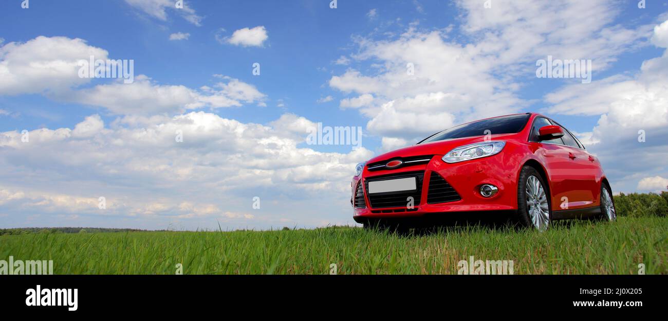 Red car on a blue sky background with white clouds. The car is standing ...