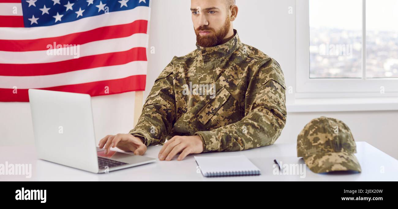 Young soldier who serves in US army sitting in office and working on ...